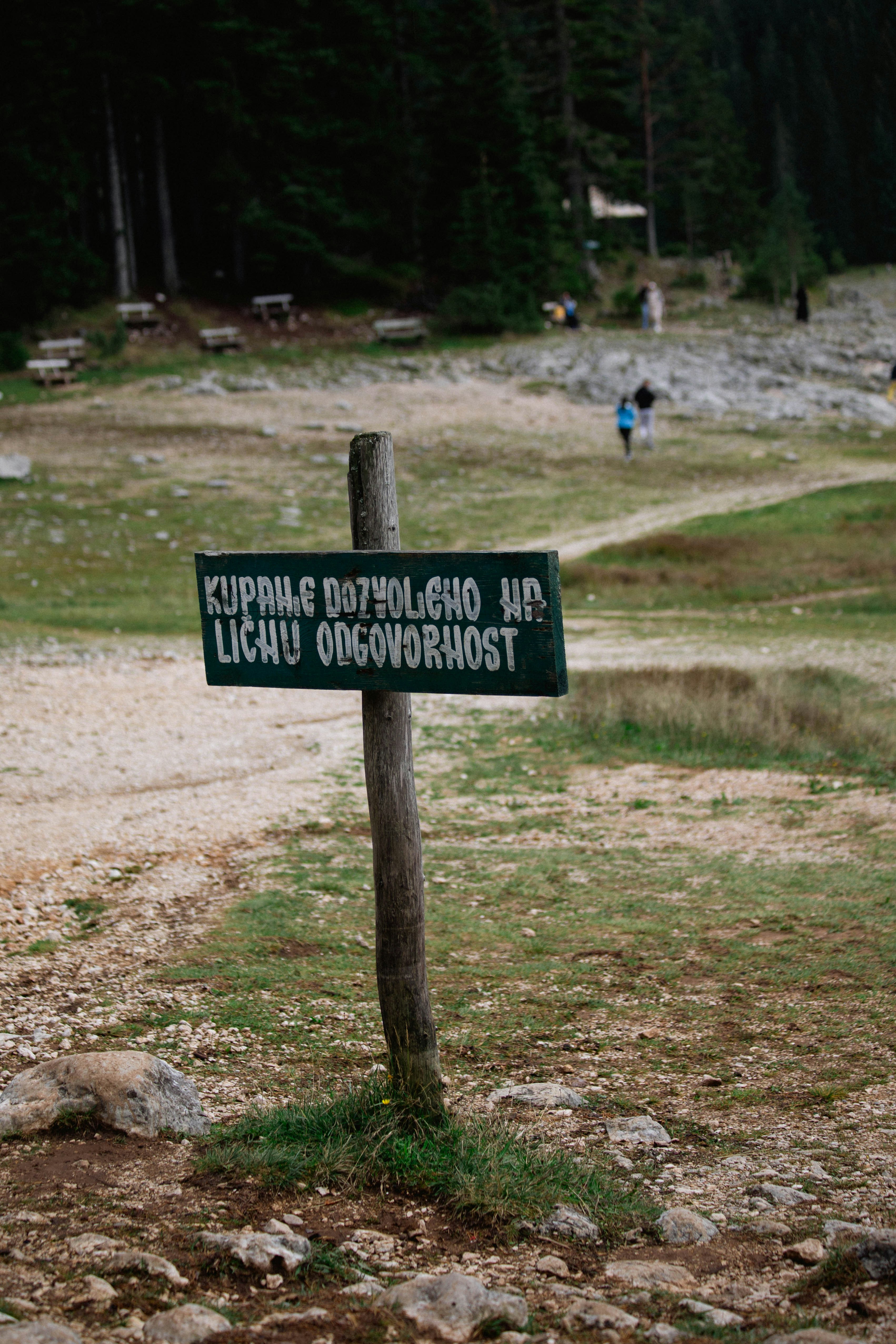 Signpost on a weathered pole marking a winding path through a rocky hillside