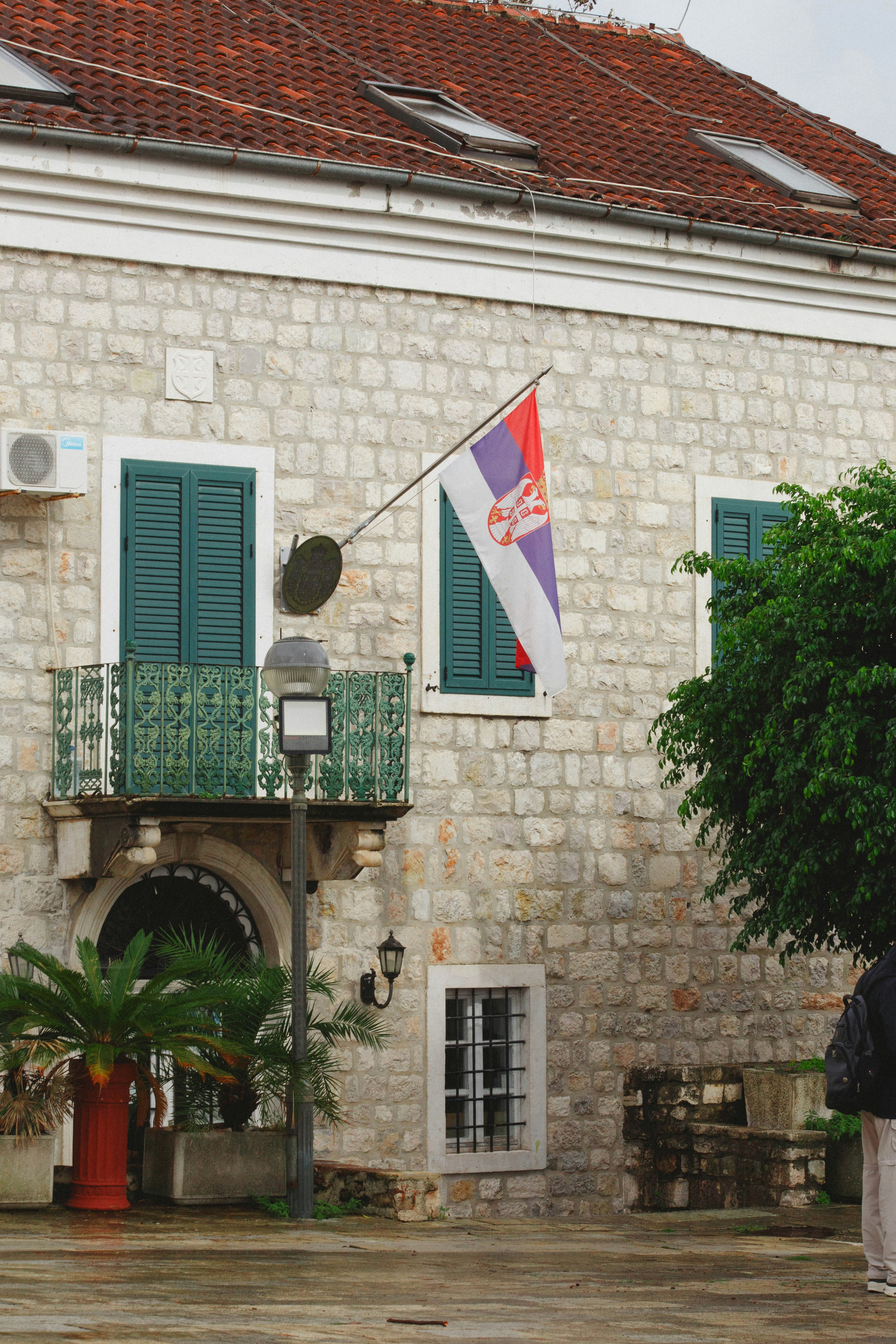 A person standing in front of a building with a flag on it