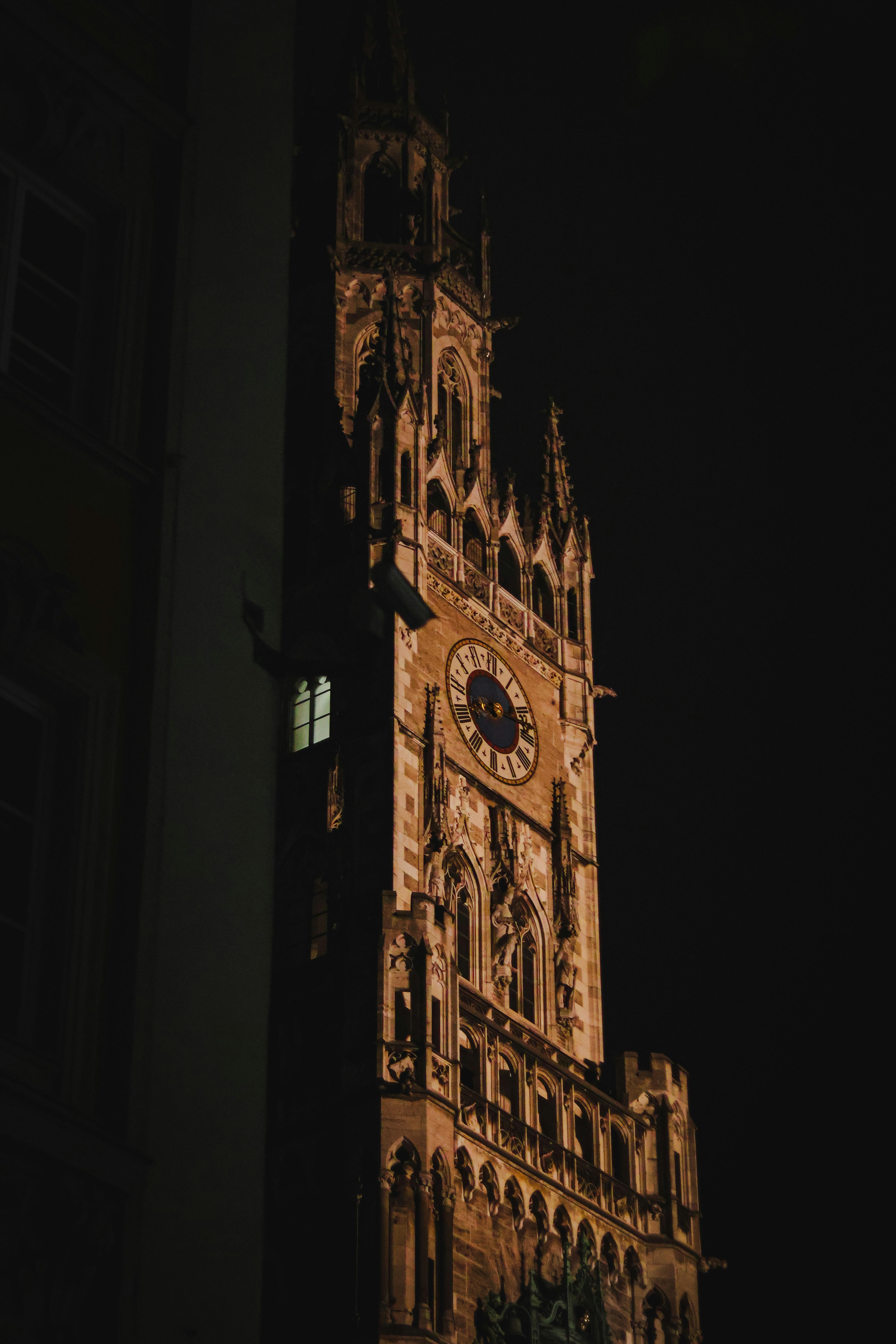 Nocturnal Clock Tower: Amber-lit Gothic Facade Reaching into Night