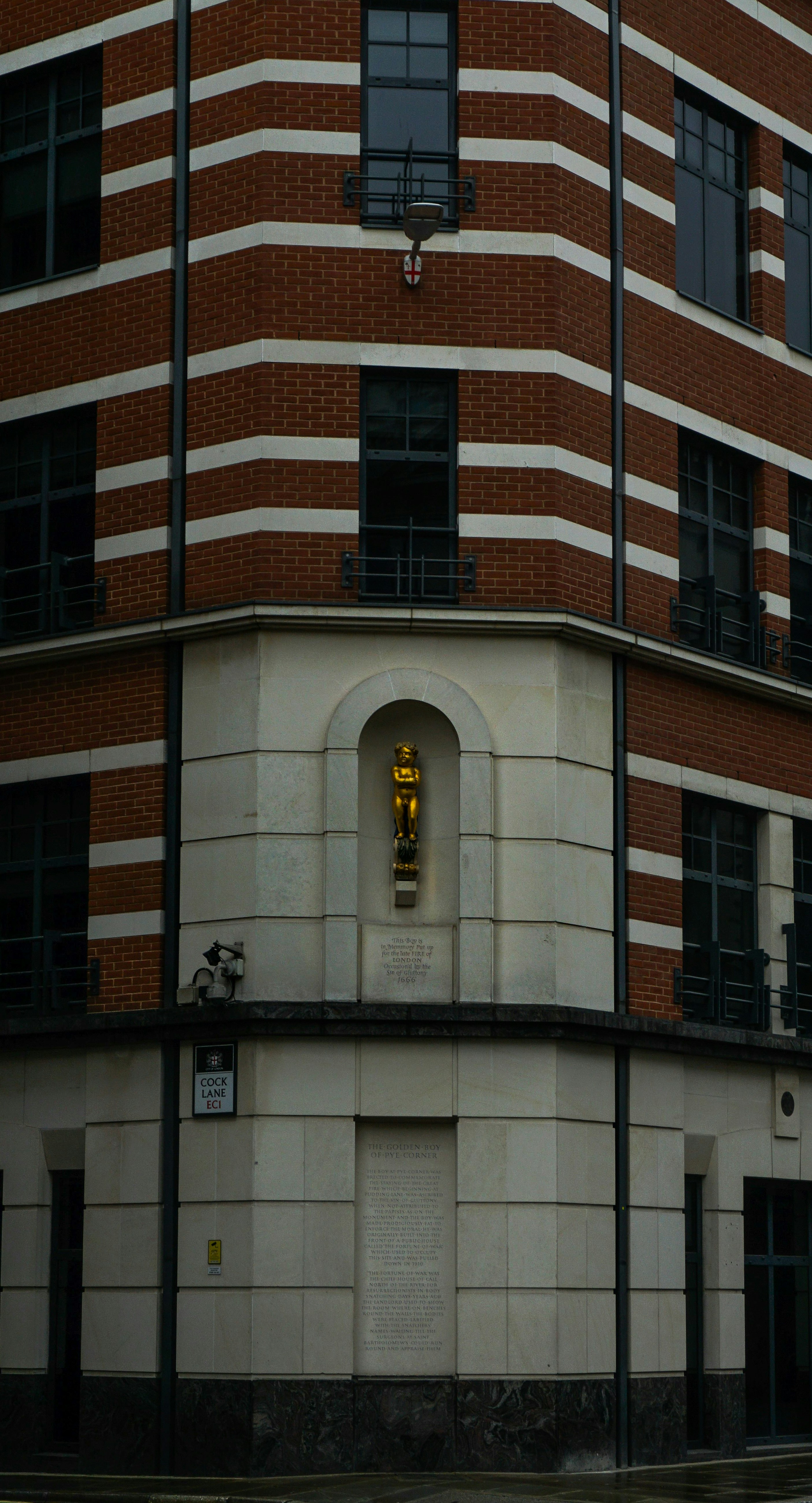 Golden Figure in a Stone Niche Framed by Red-Brick Architecture