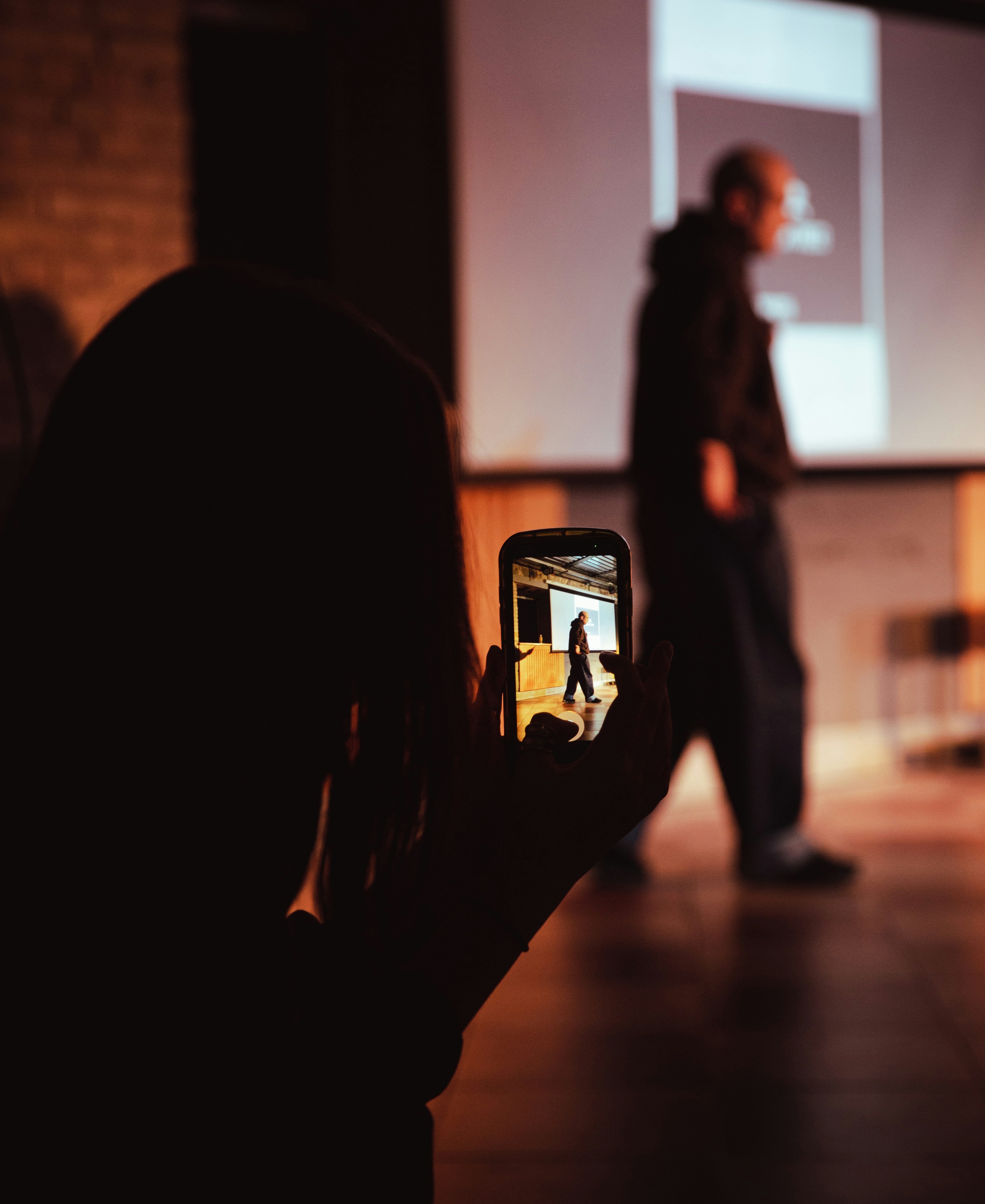 A person taking a picture of a man on a projector screen photo – Free ...