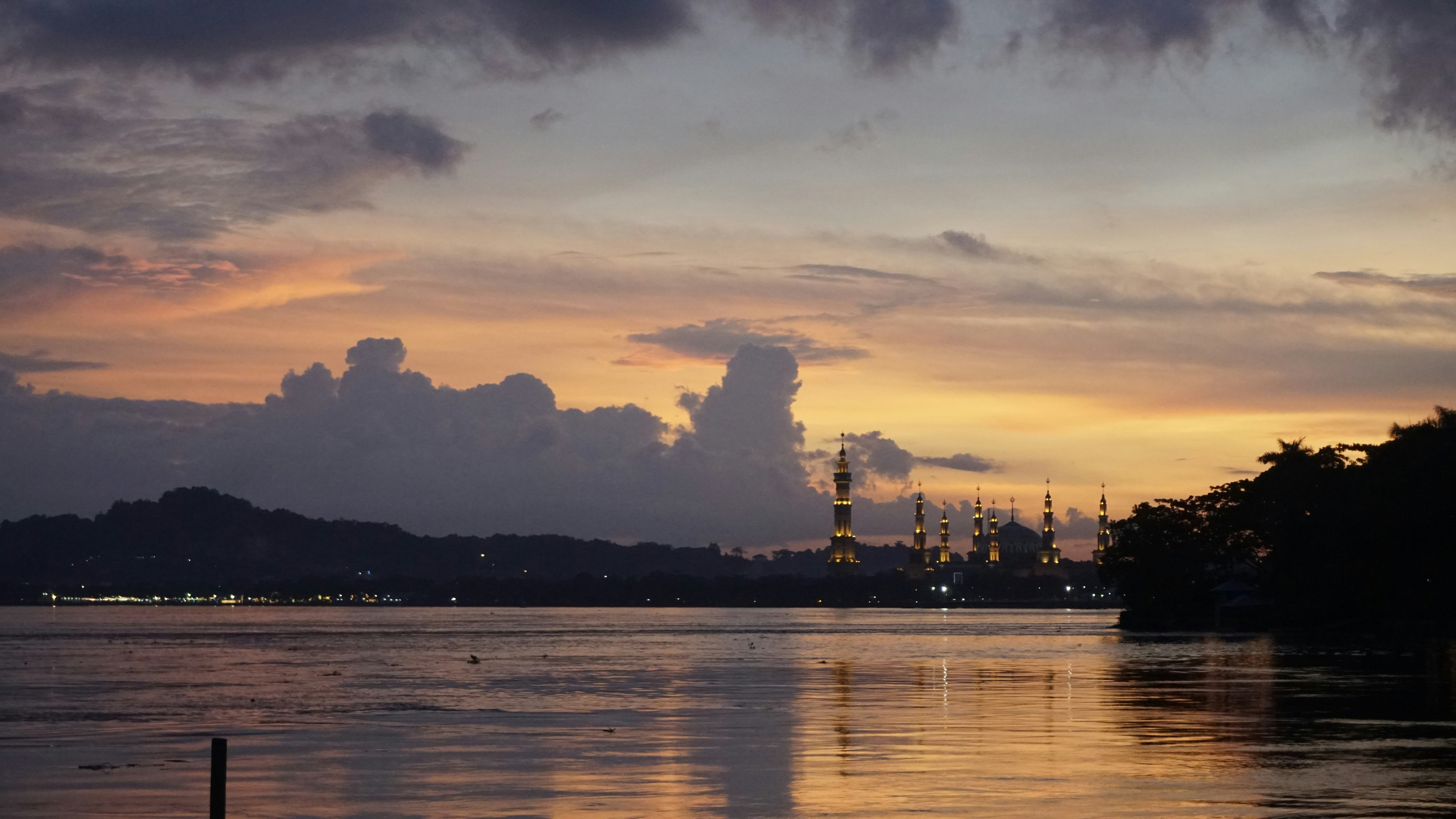 Silhouetted cityscape against a vibrant sunset sky over Mahakam River.