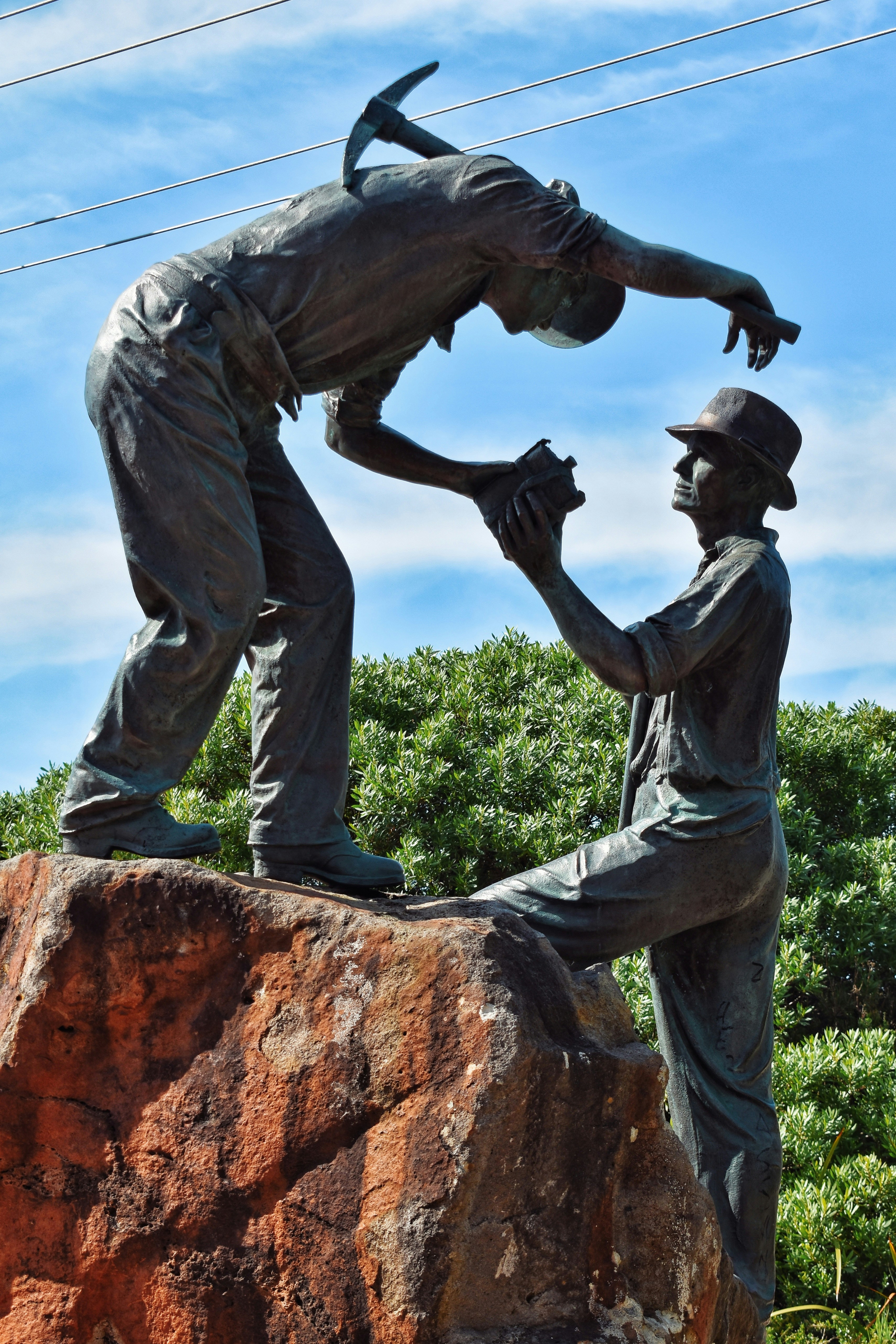 Handshake on the Summit: A Bronze Gesture of Trust atop Weathered Stone
