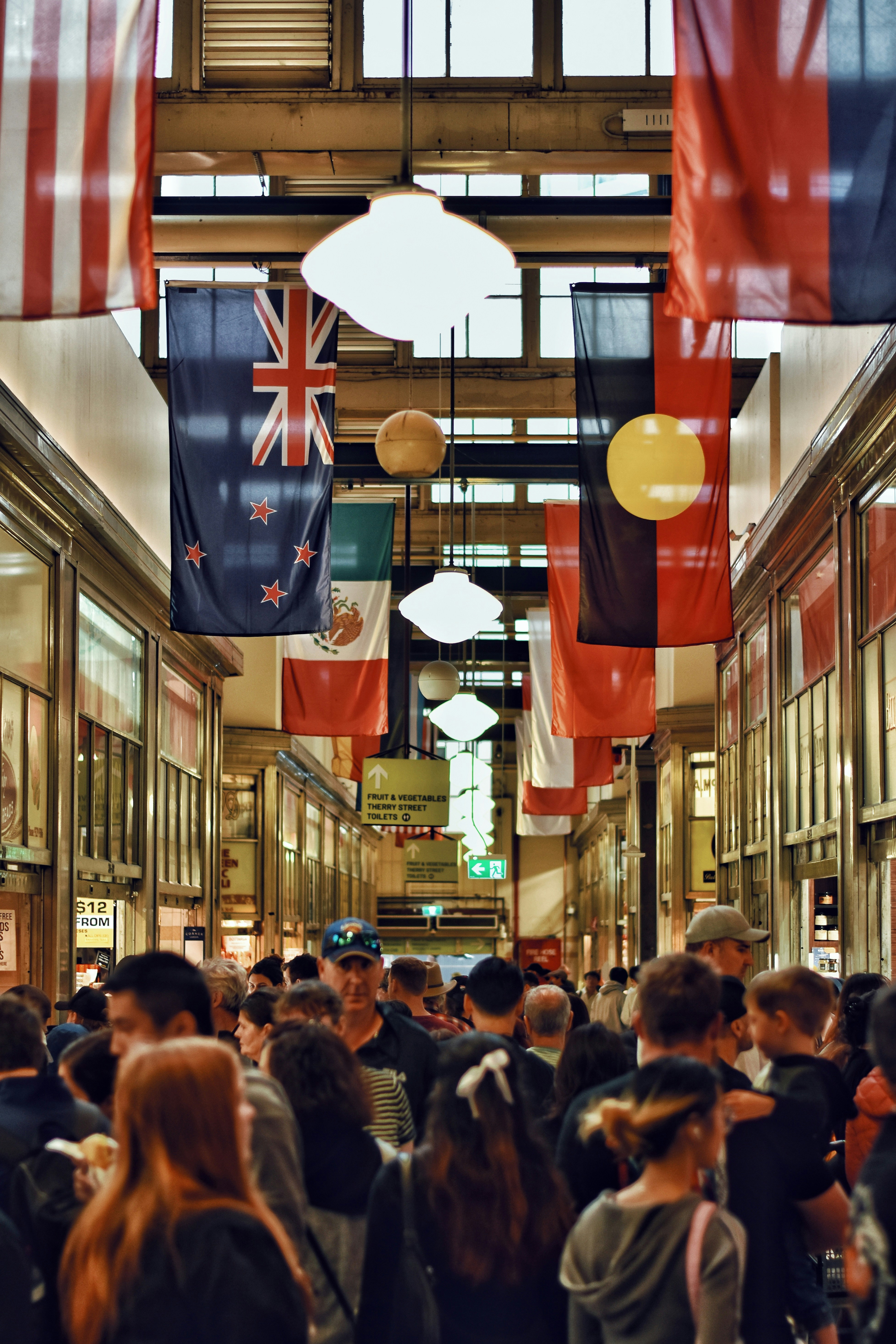 A group of people walking down a hallway with flags hanging from the ...