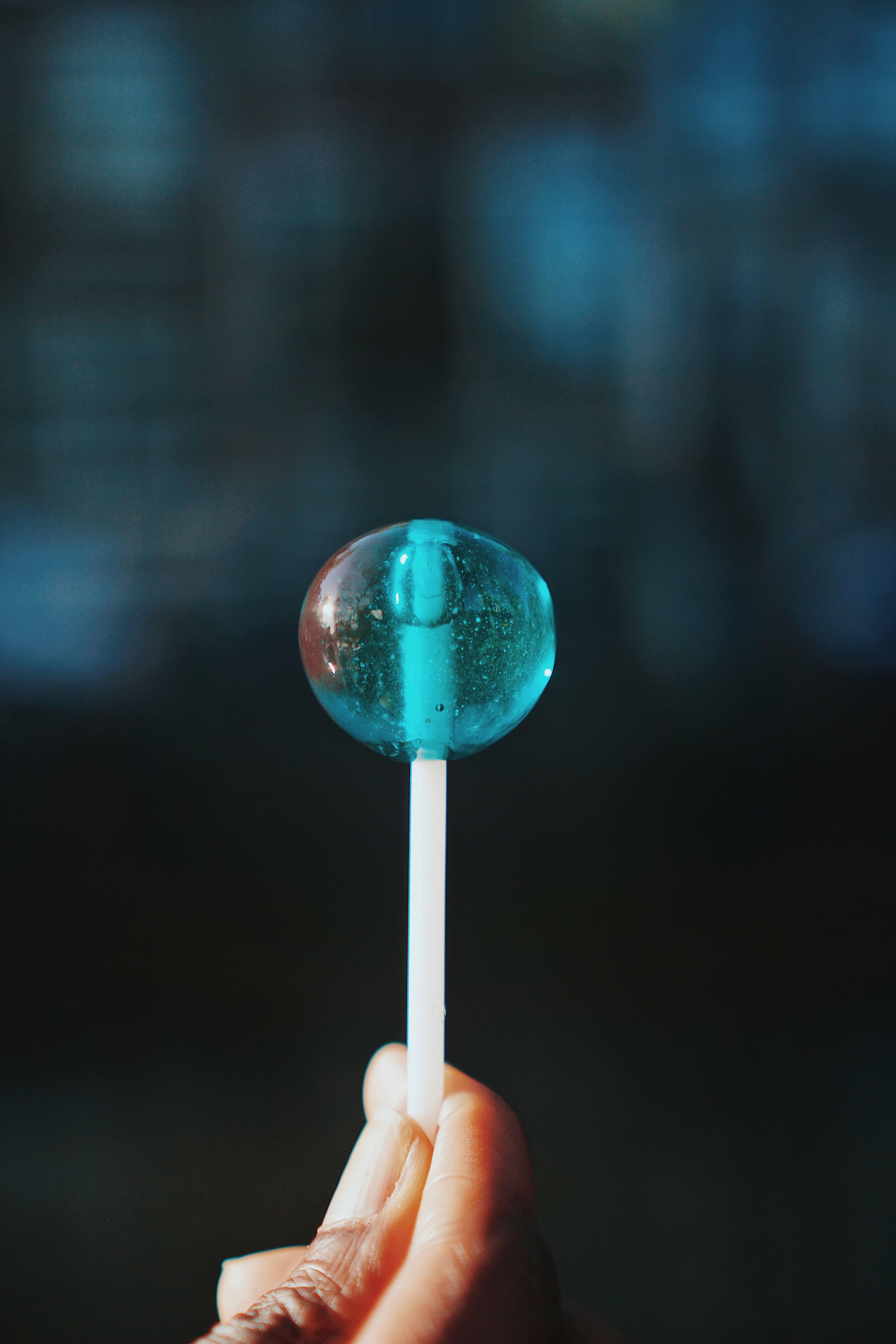 A person holding a lollipop in their hand photo – Free Candy Image on ...