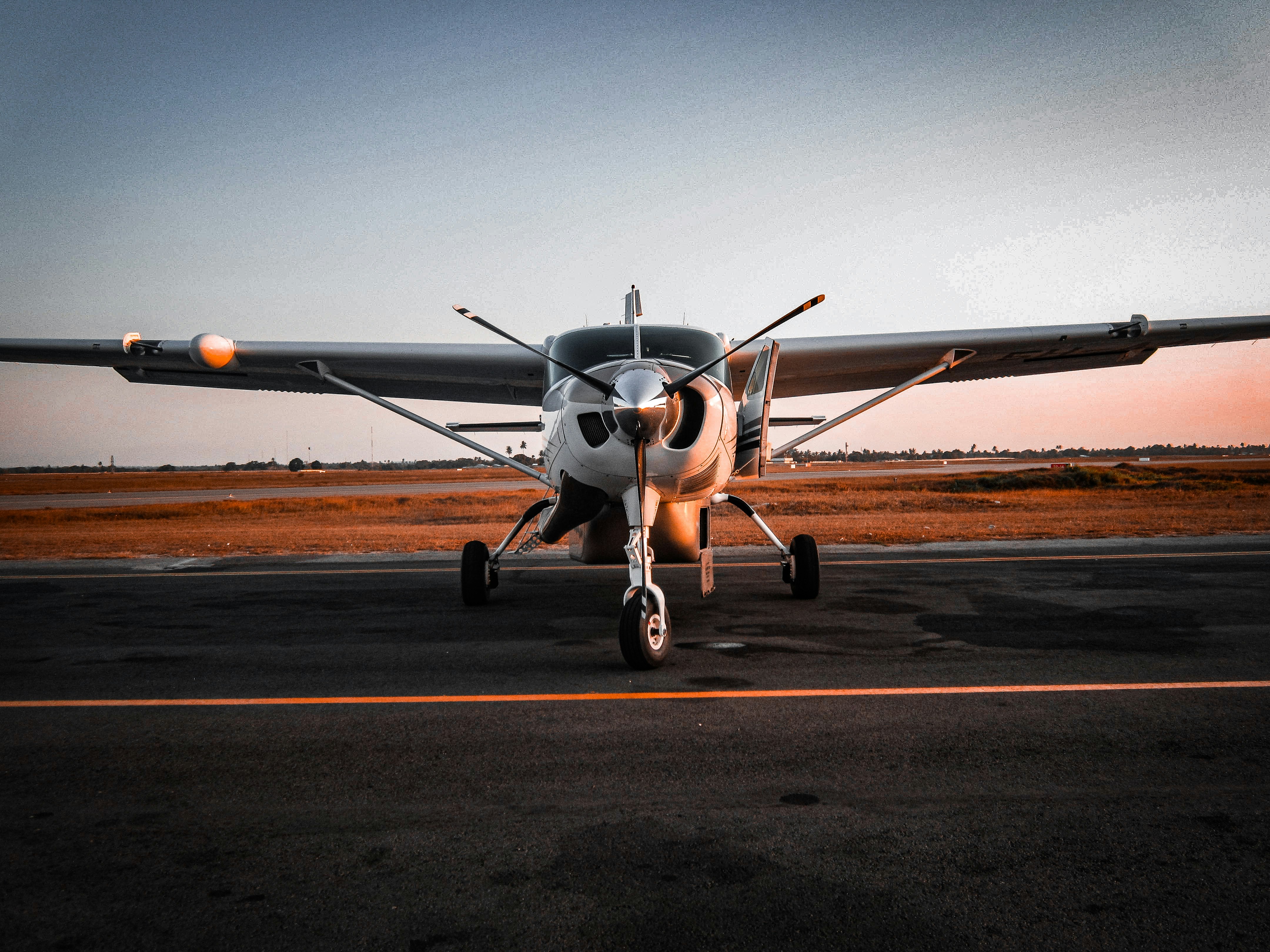 "Captured at Dar es Salaam's Domestic Airport during a serene sunset, this image encapsulates the preparation to takeoff, heading towards the idyllic island of Zanzibar, Tanzania. The soft glow of the setting sun adds warmth to the moment, making it a perfect blend of travel and natural beauty."