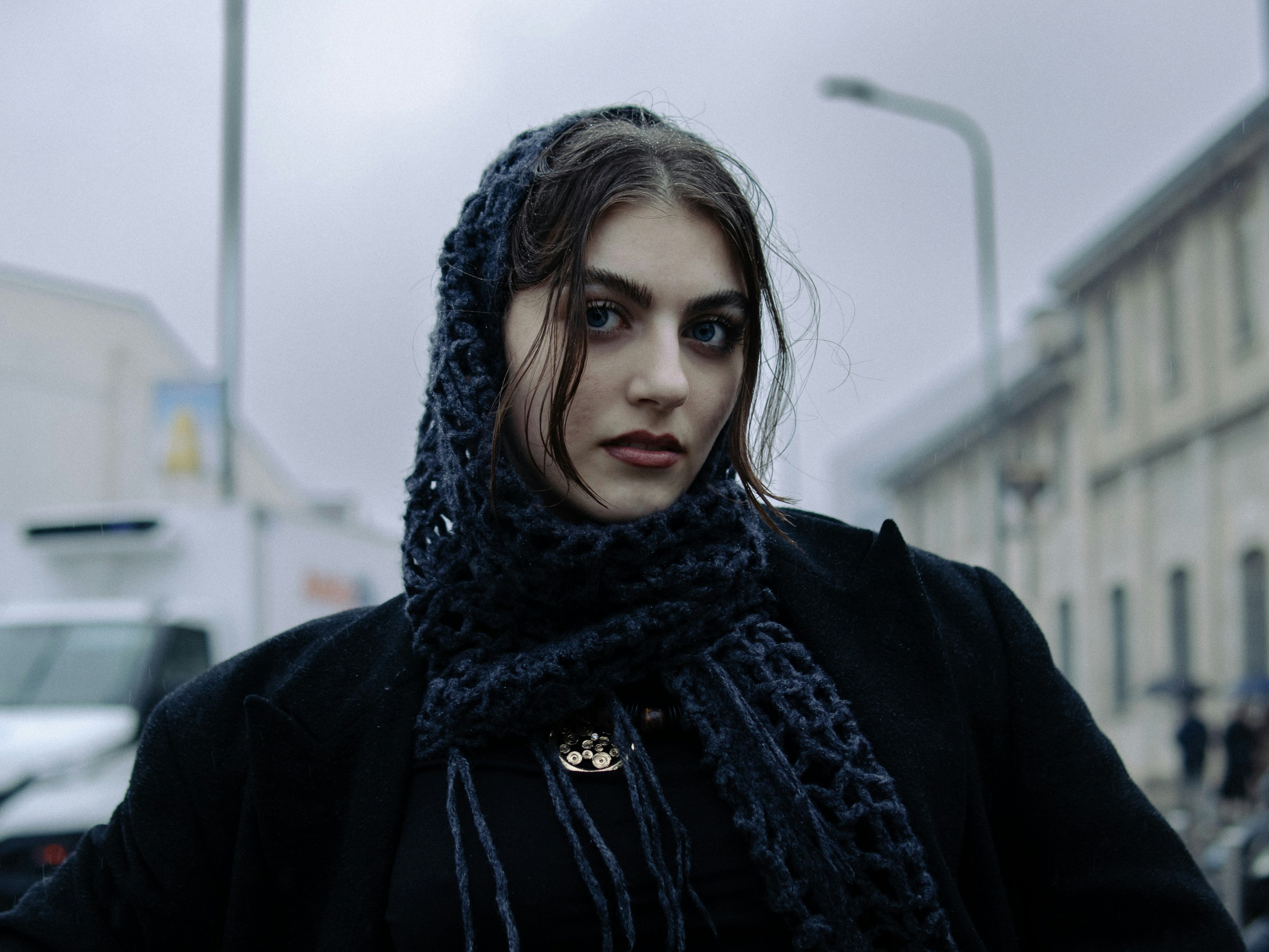 A woman wearing a scarf and a black coat