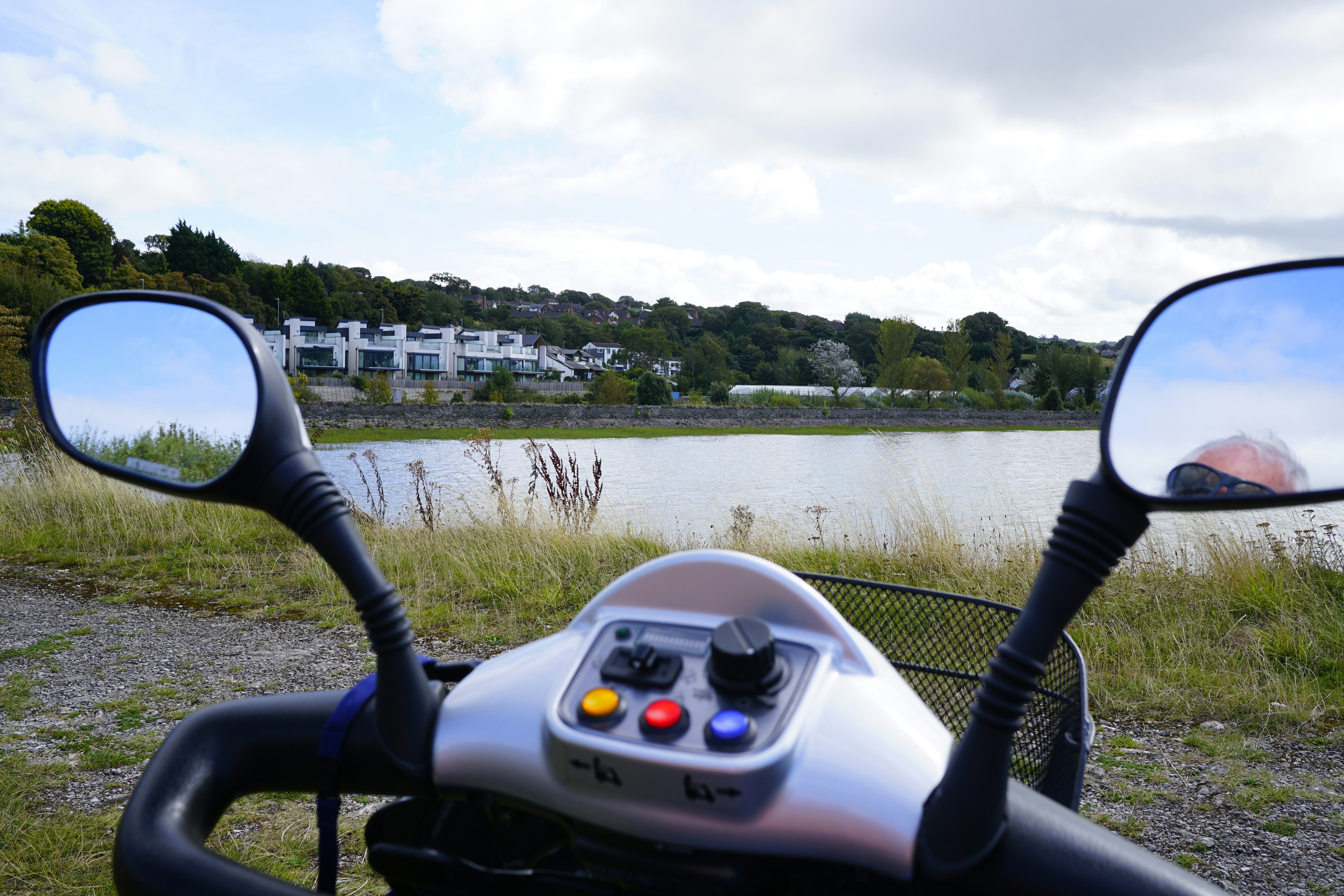 Close-up of a scooter's cockpit framing a lakeside landscape