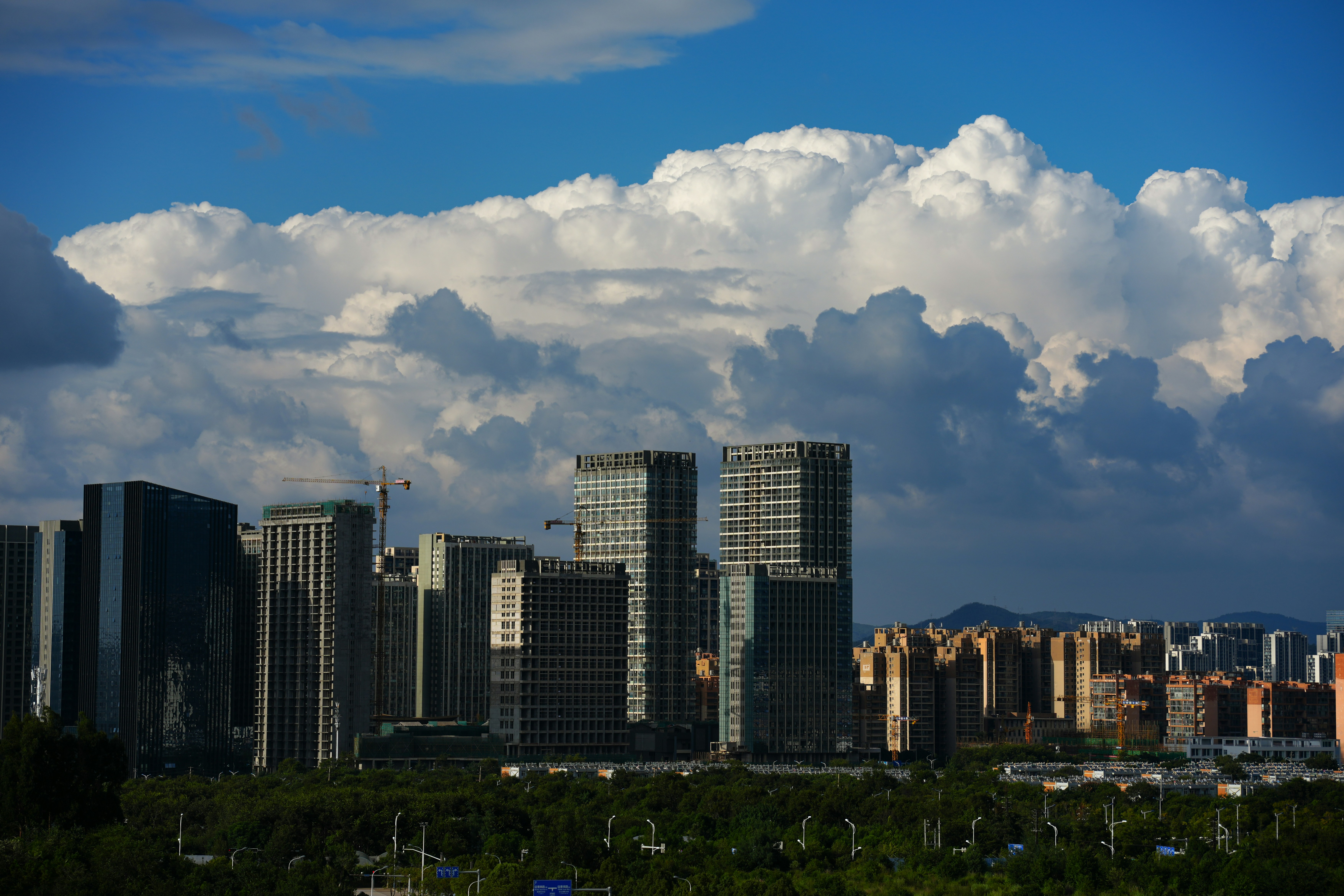Modern skyscrapers rise against a backdrop of dramatic clouds, showcasing the contrast between architecture and nature's beauty.