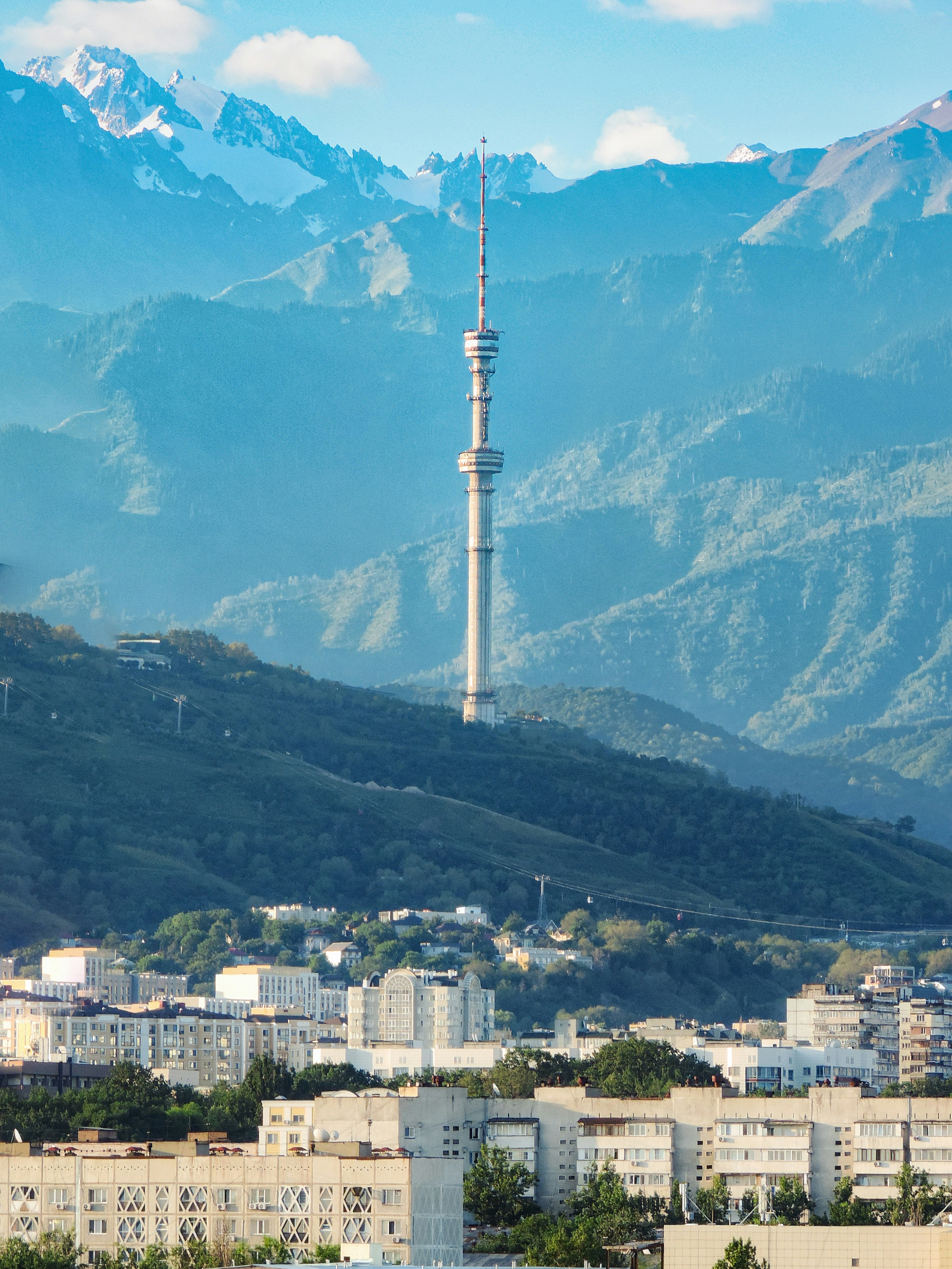Spire Over the Valley: A Telephoto Portrait of City and Alpine Peaks