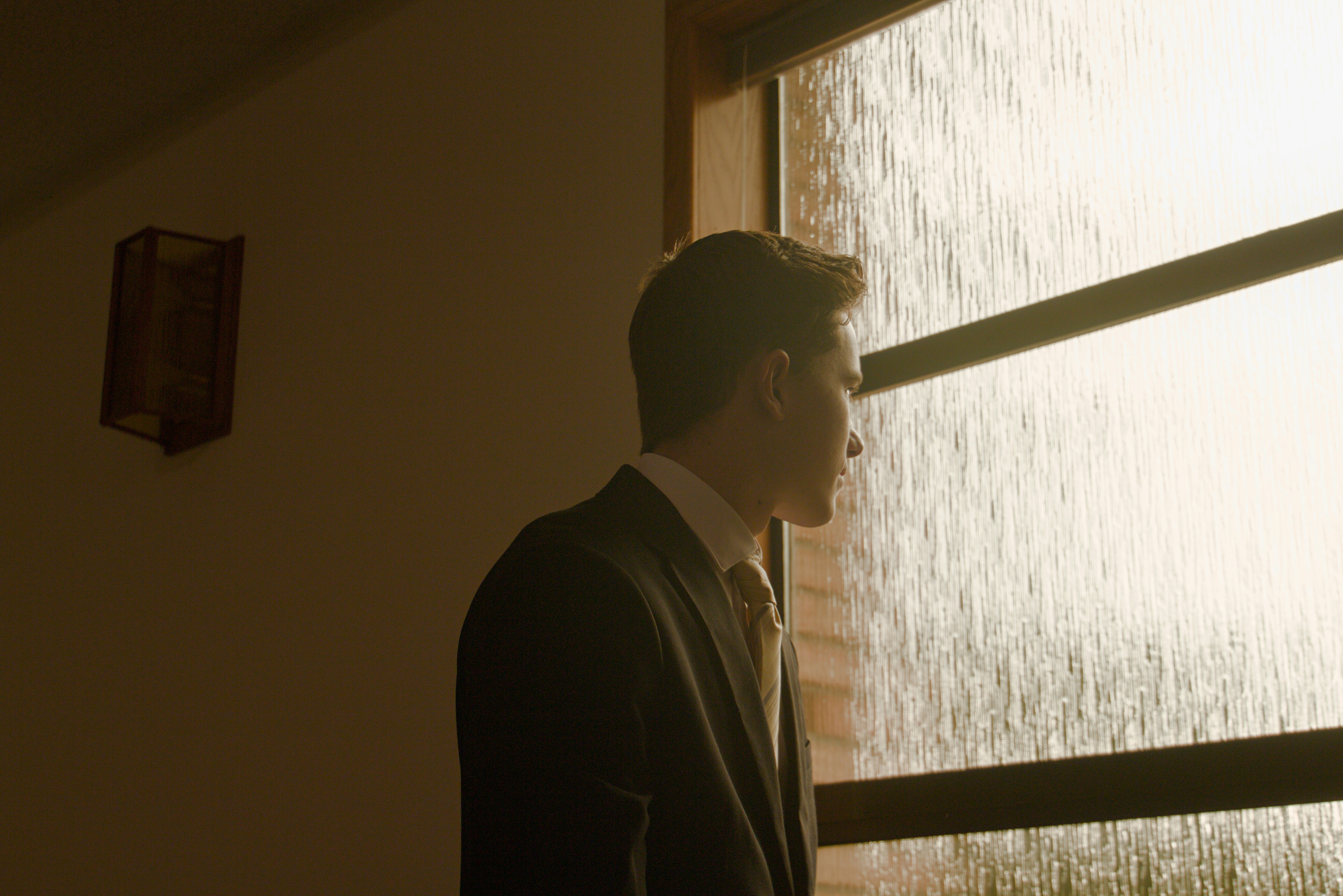 A man in a suit looking out of a window photo – Free Portrait Image on ...