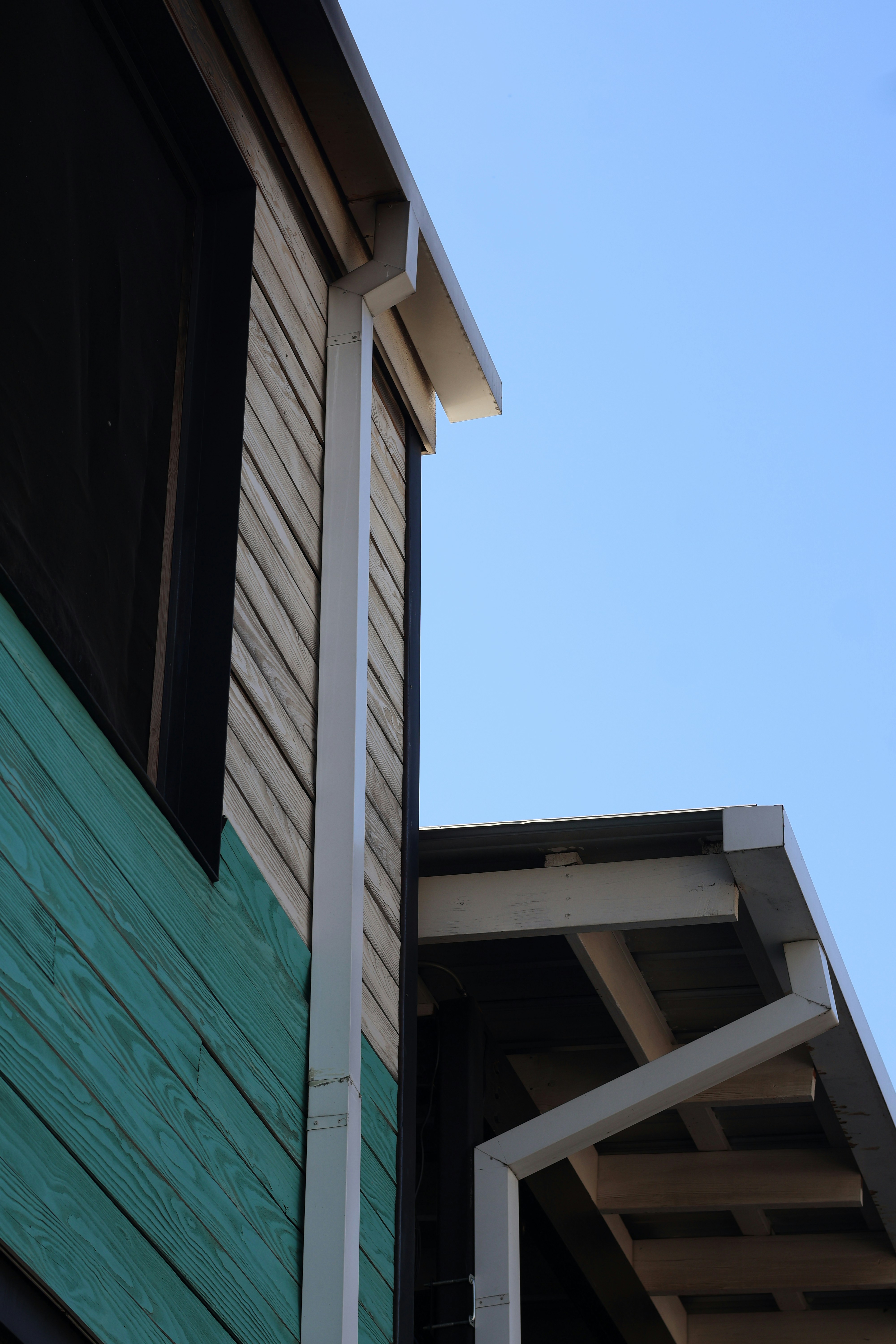 Angular view of a modern building showcasing contrasting wooden textures and a clear blue sky.