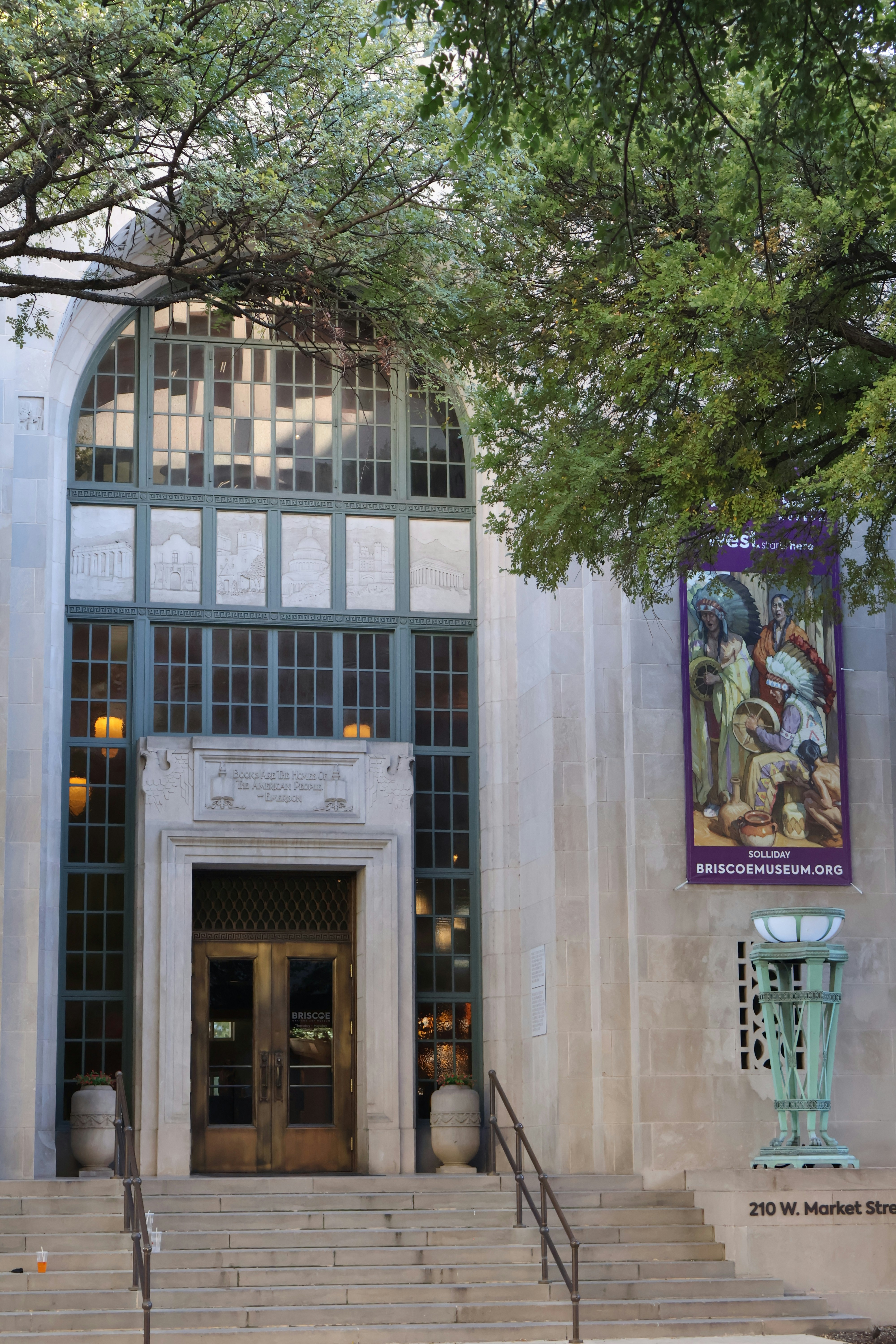 Arched Entrance at Briscoe Museum: Stone Steps, Glass Doors, and a Bannered Façade