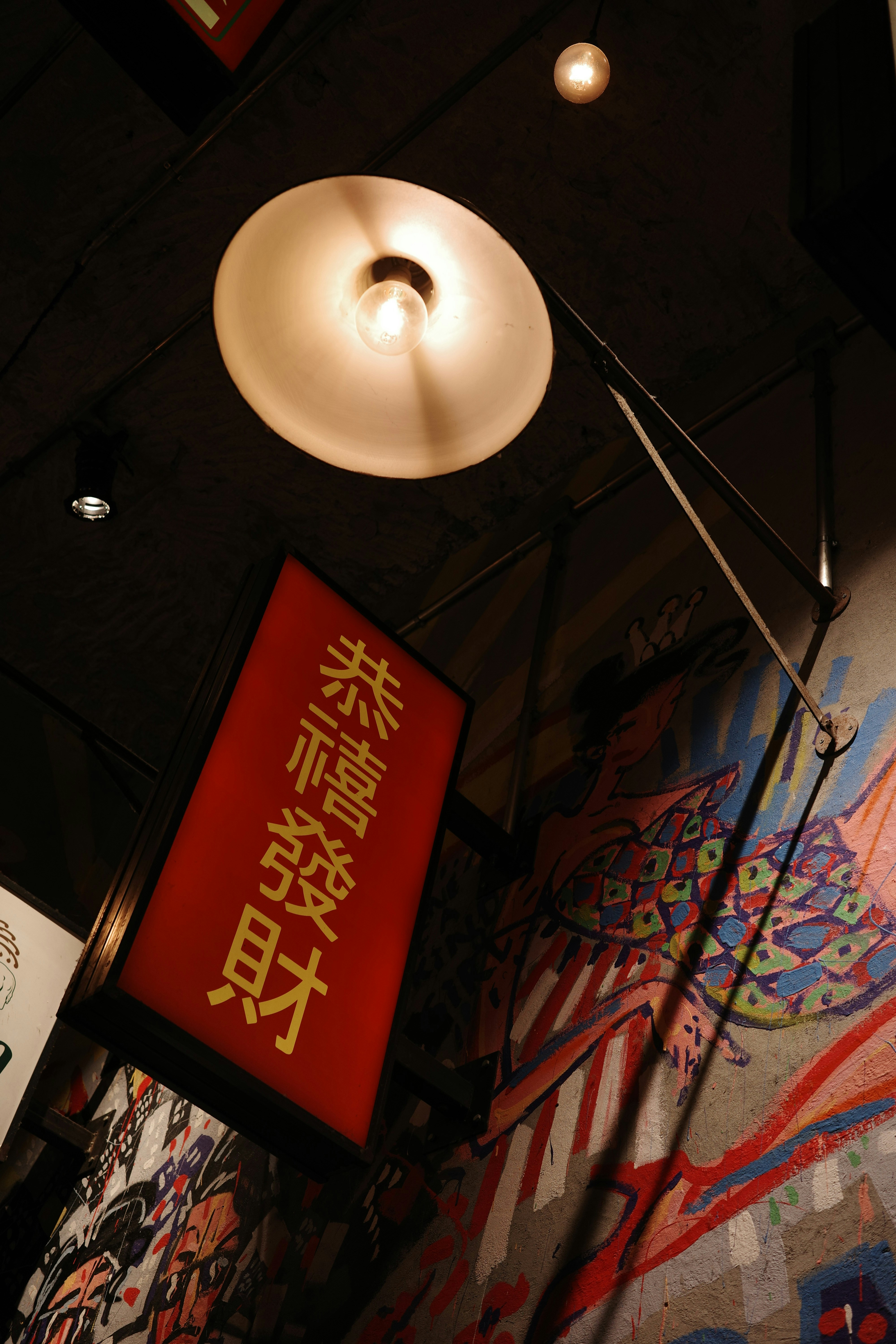 Red Chinese Sign Amid Graffiti Under Warm Overhead Light