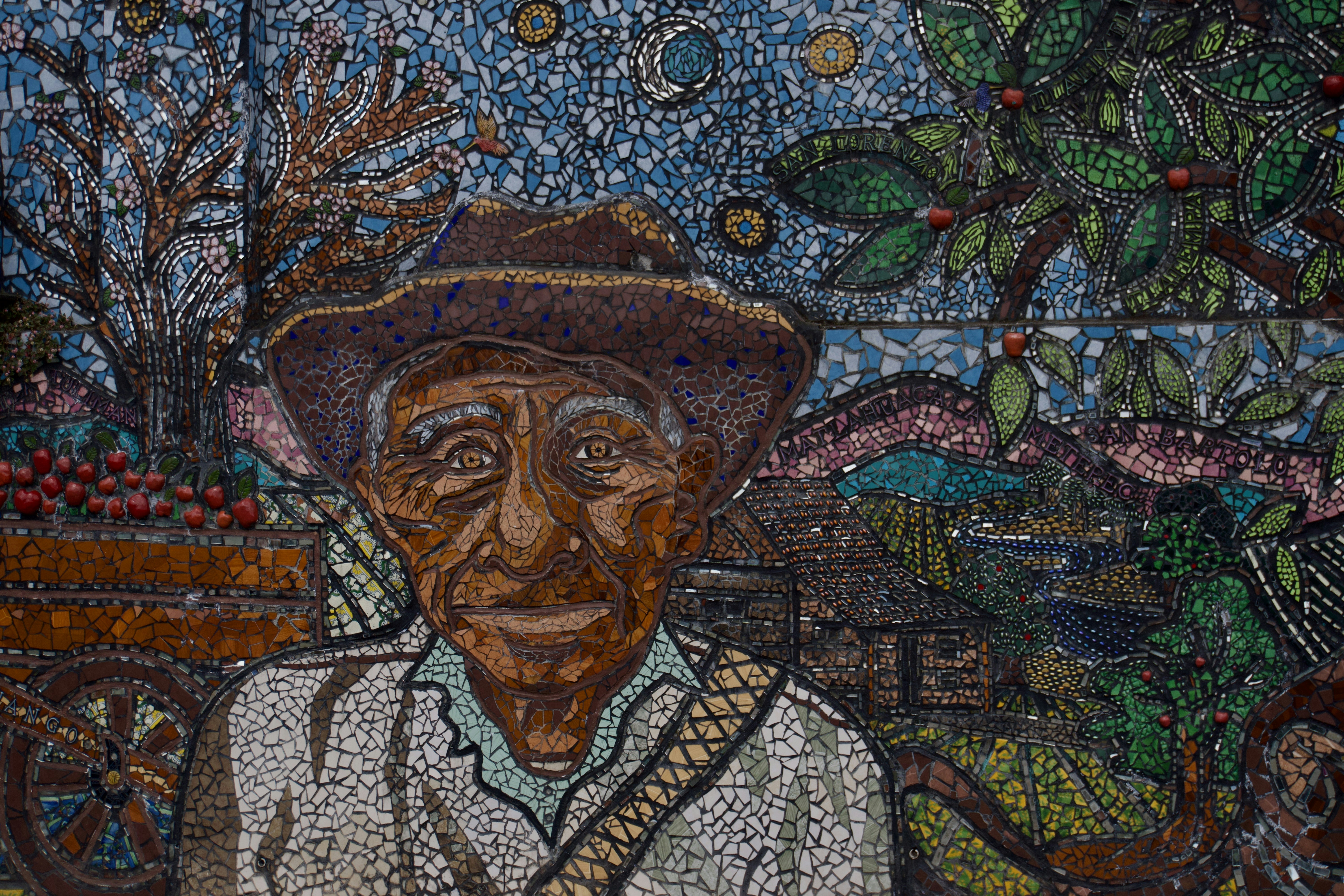 Intricate mosaic depicting an elderly man with a hat, surrounded by a colorful landscape and trees.