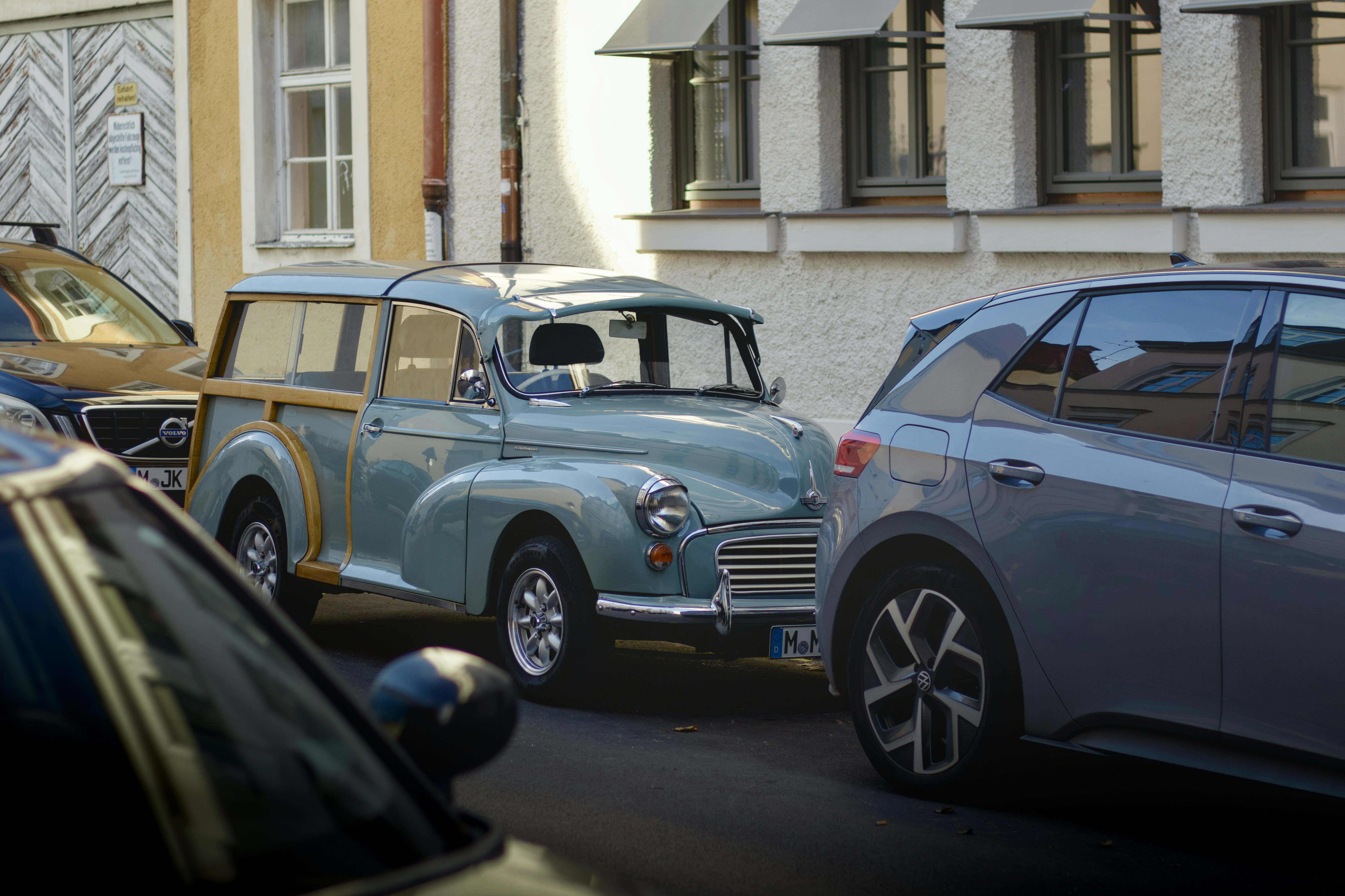 Classic car parked on a street between contemporary vehicles under soft daylight.