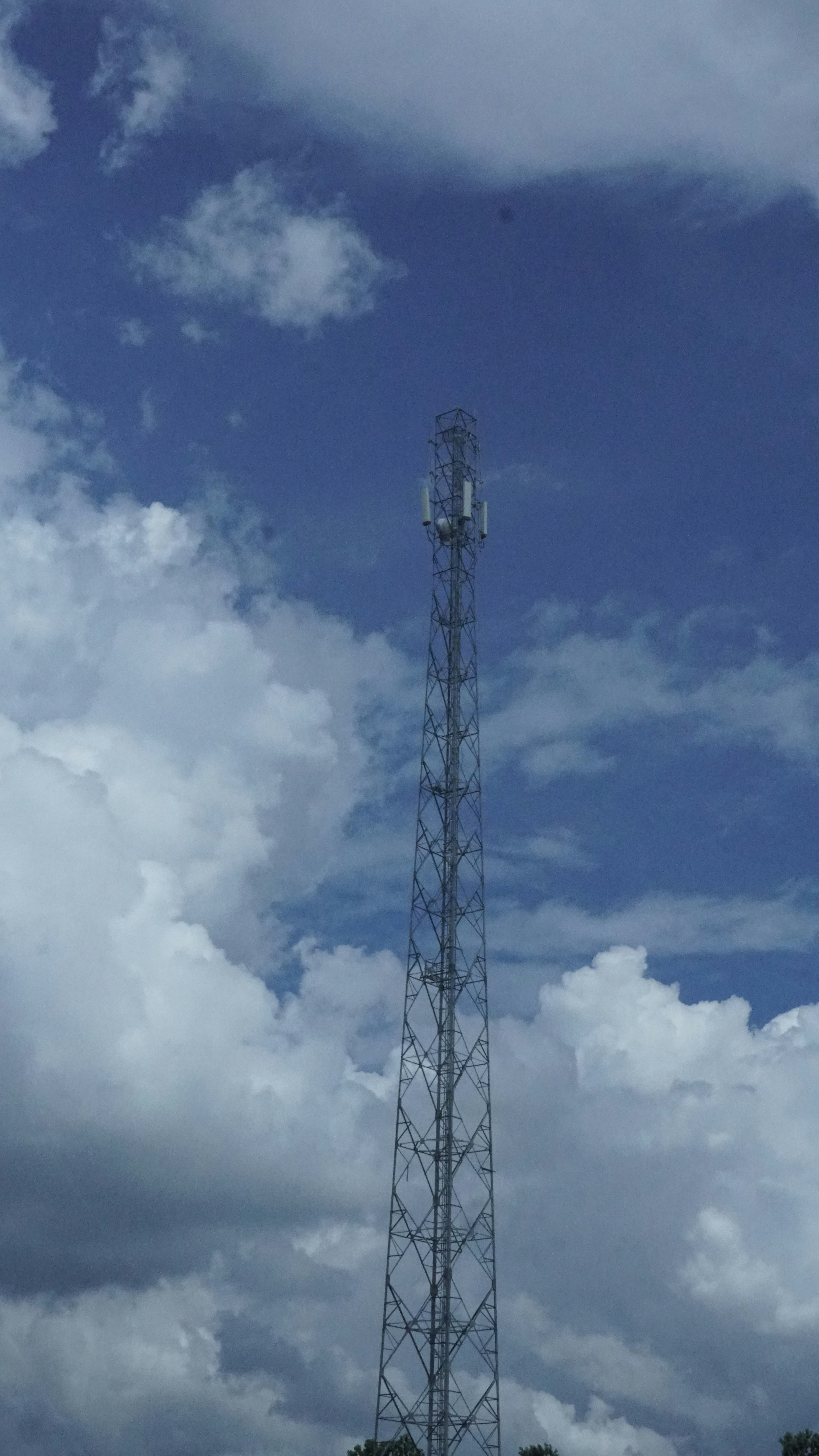 A tall communication tower rises against a backdrop of dynamic clouds, symbolizing connectivity and technology.