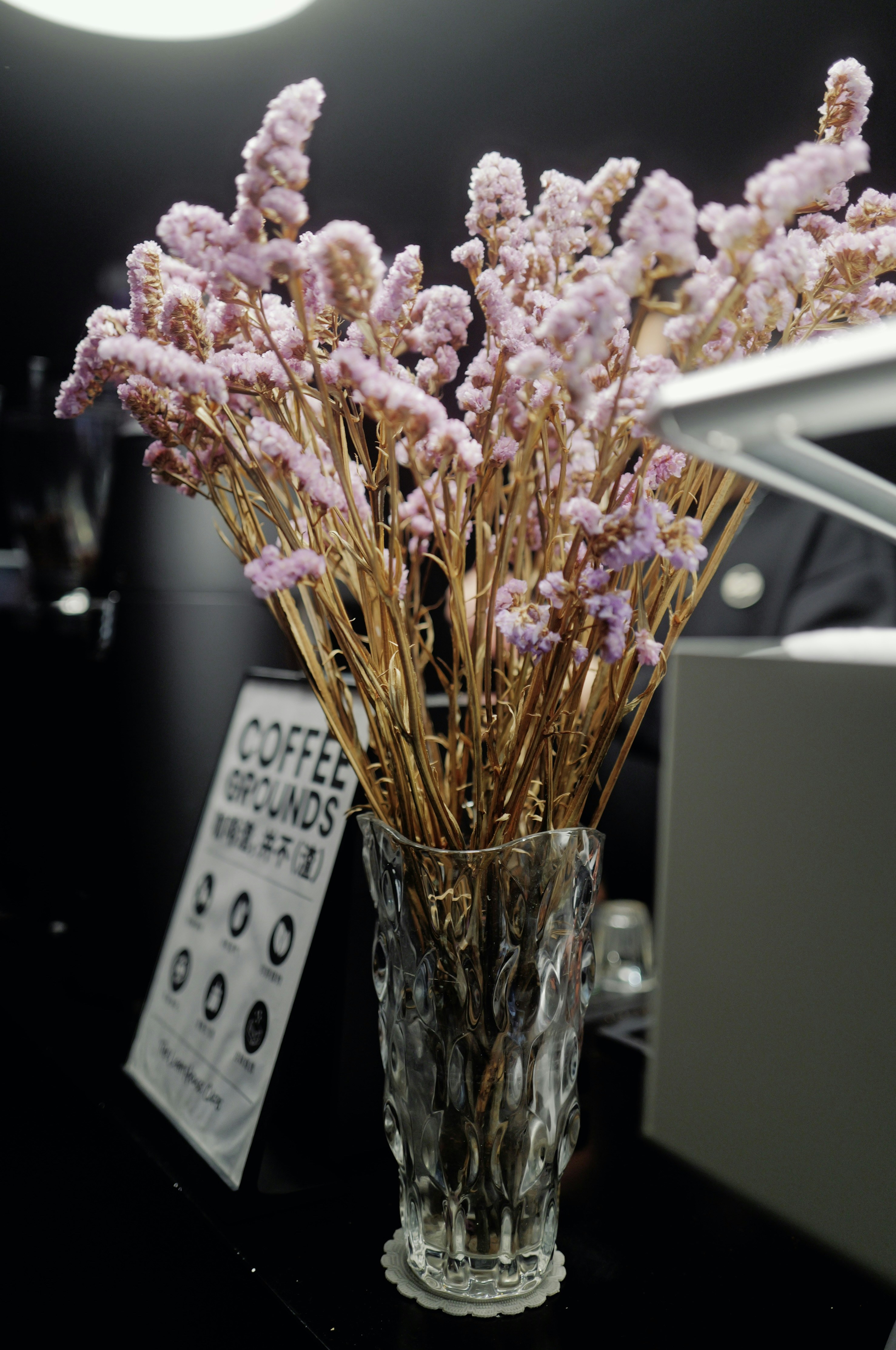 Dried Pink Sprigs in a Faceted Vase Beneath Café Ambient Light
