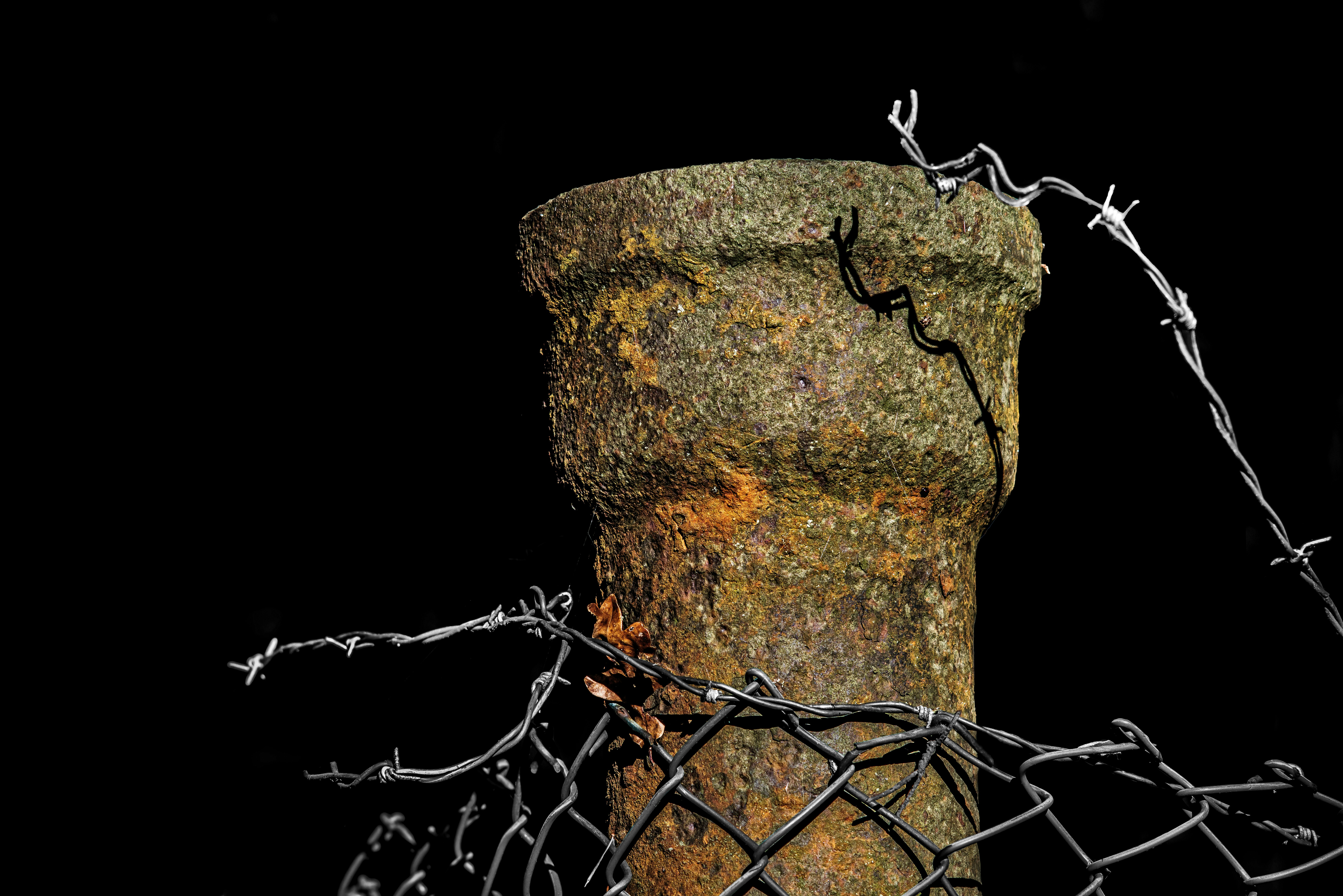 Rust-Worn Sentinel: A Barbed-Wire Post Standing in Night