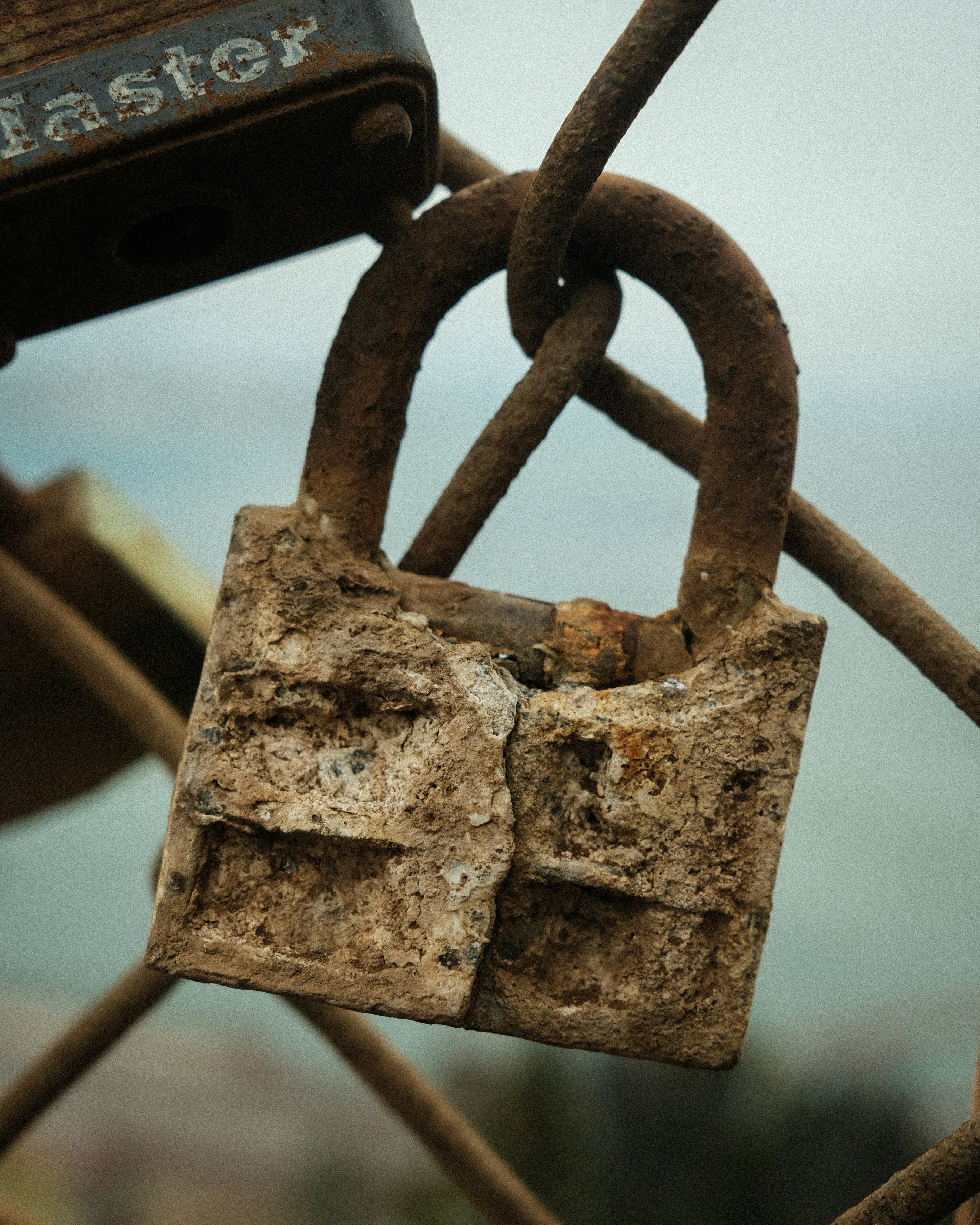 Rust and Chain: A Close-Up of Weathered Locks and Barbed Fences