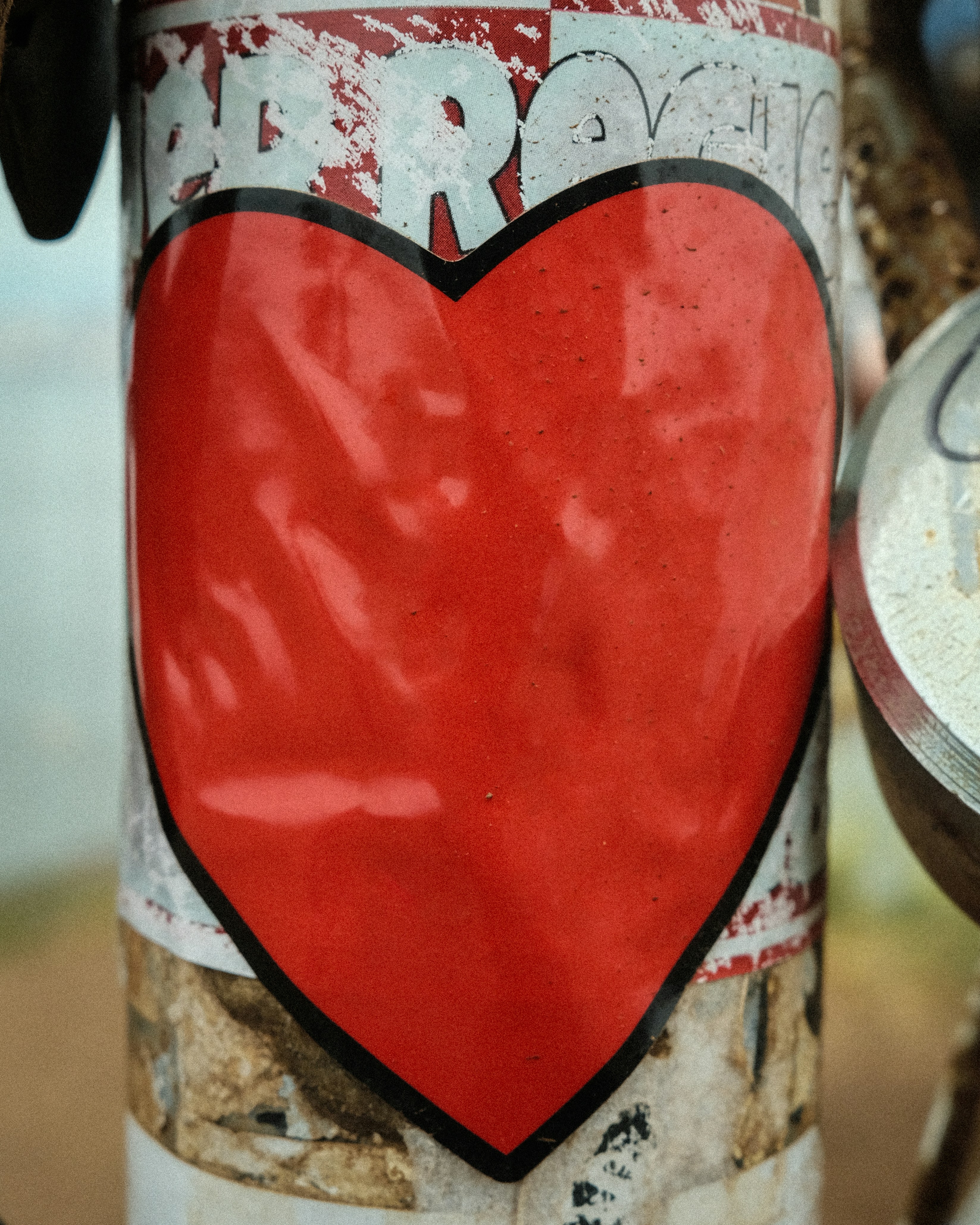 Crimson Heart Sticker Clinging to a Weathered Metal Post
