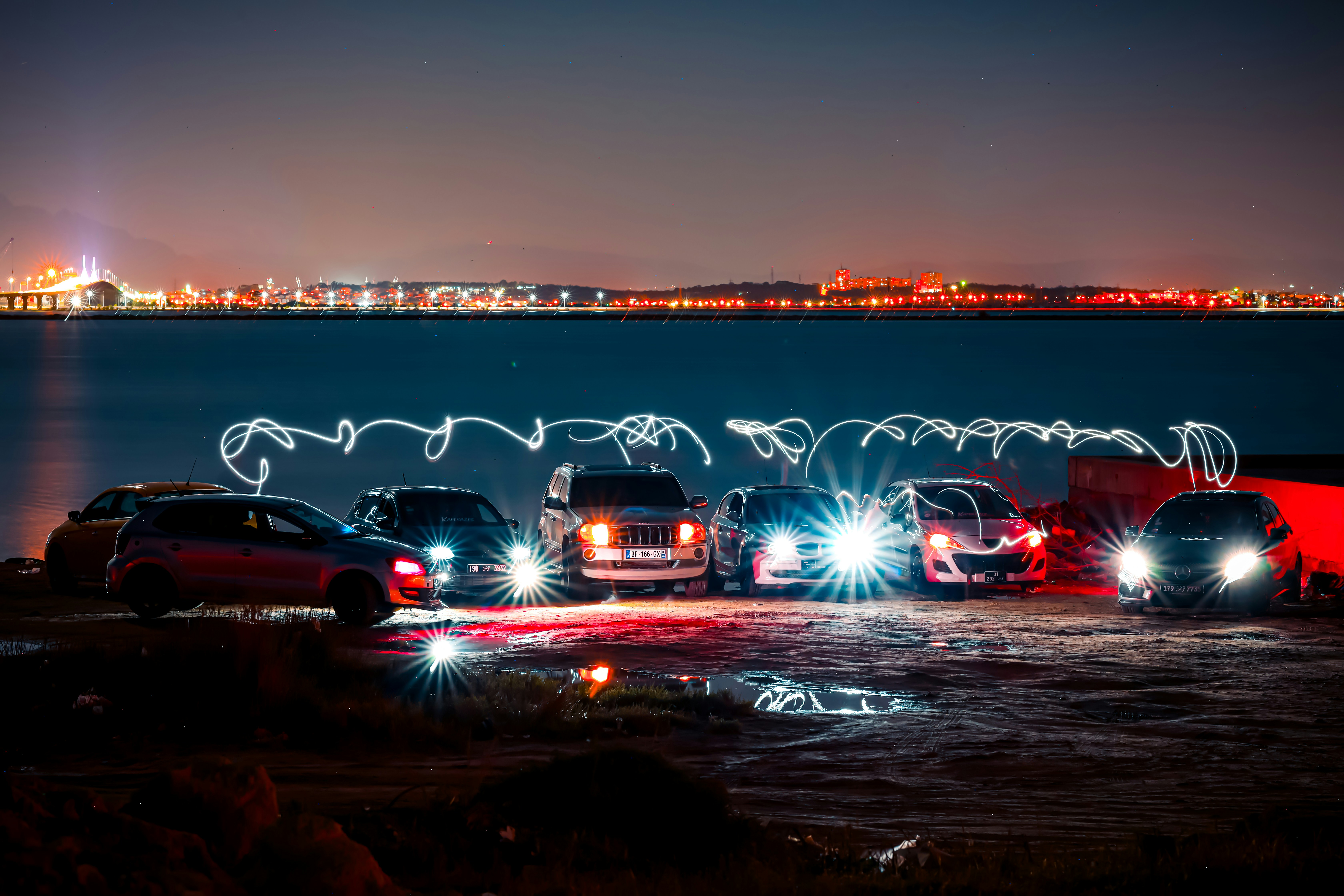 Harbor Row at Night: Neon Headlights tracing arcs over a calm shoreline