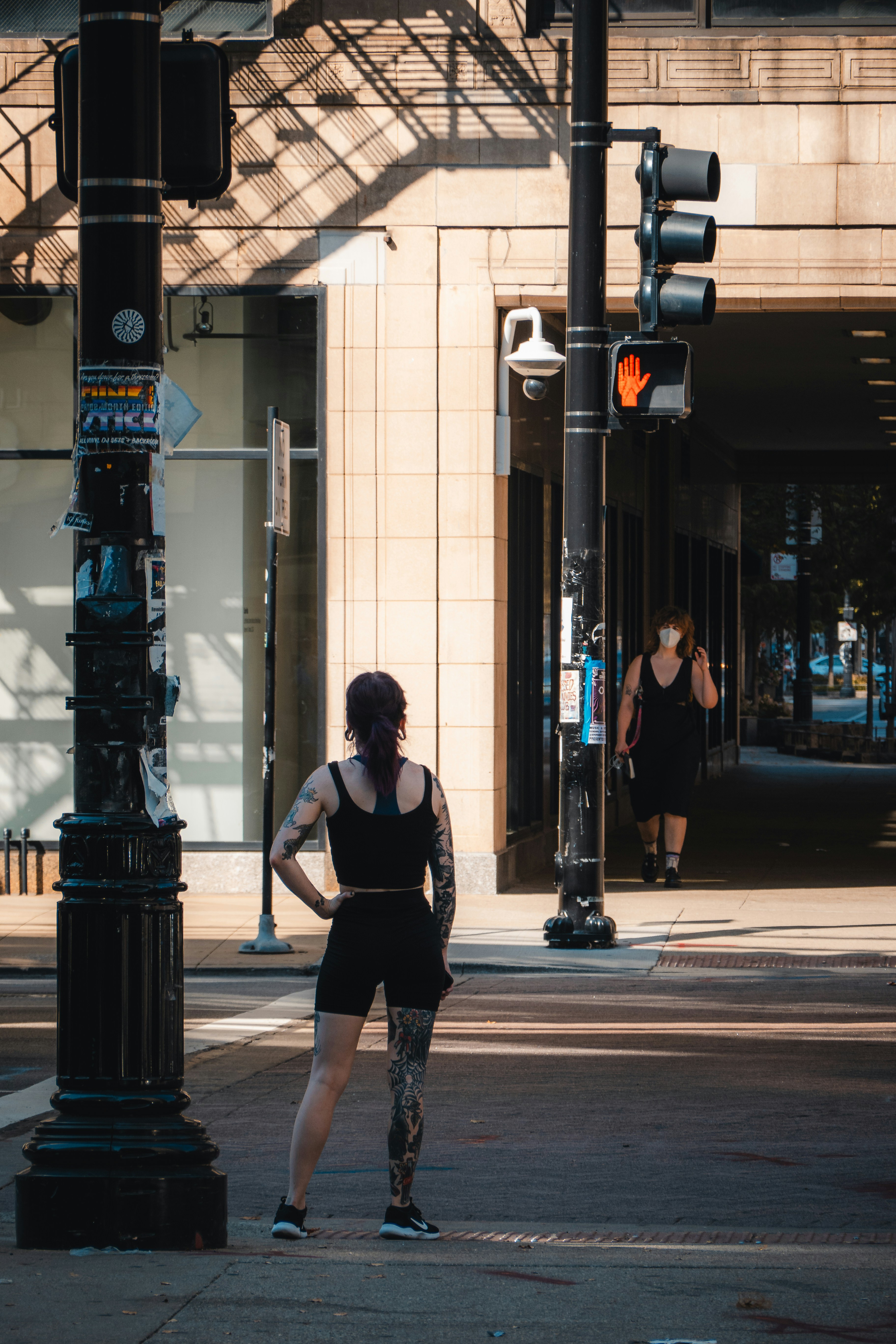A woman standing on a street corner next to a traffic light photo ...