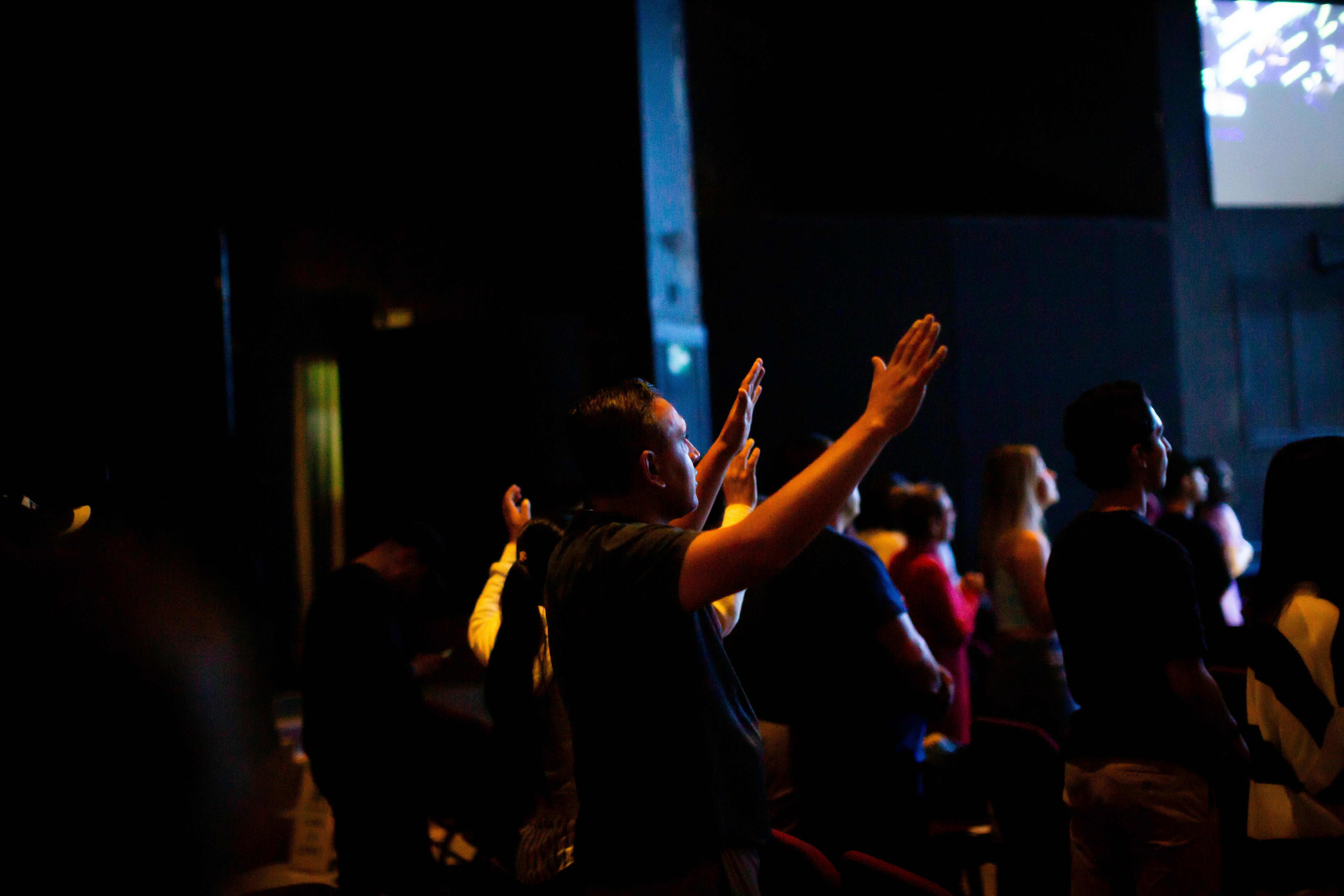 Congregants with raised hands participate in a moment of worship during a service, capturing a sense of community and devotion.
