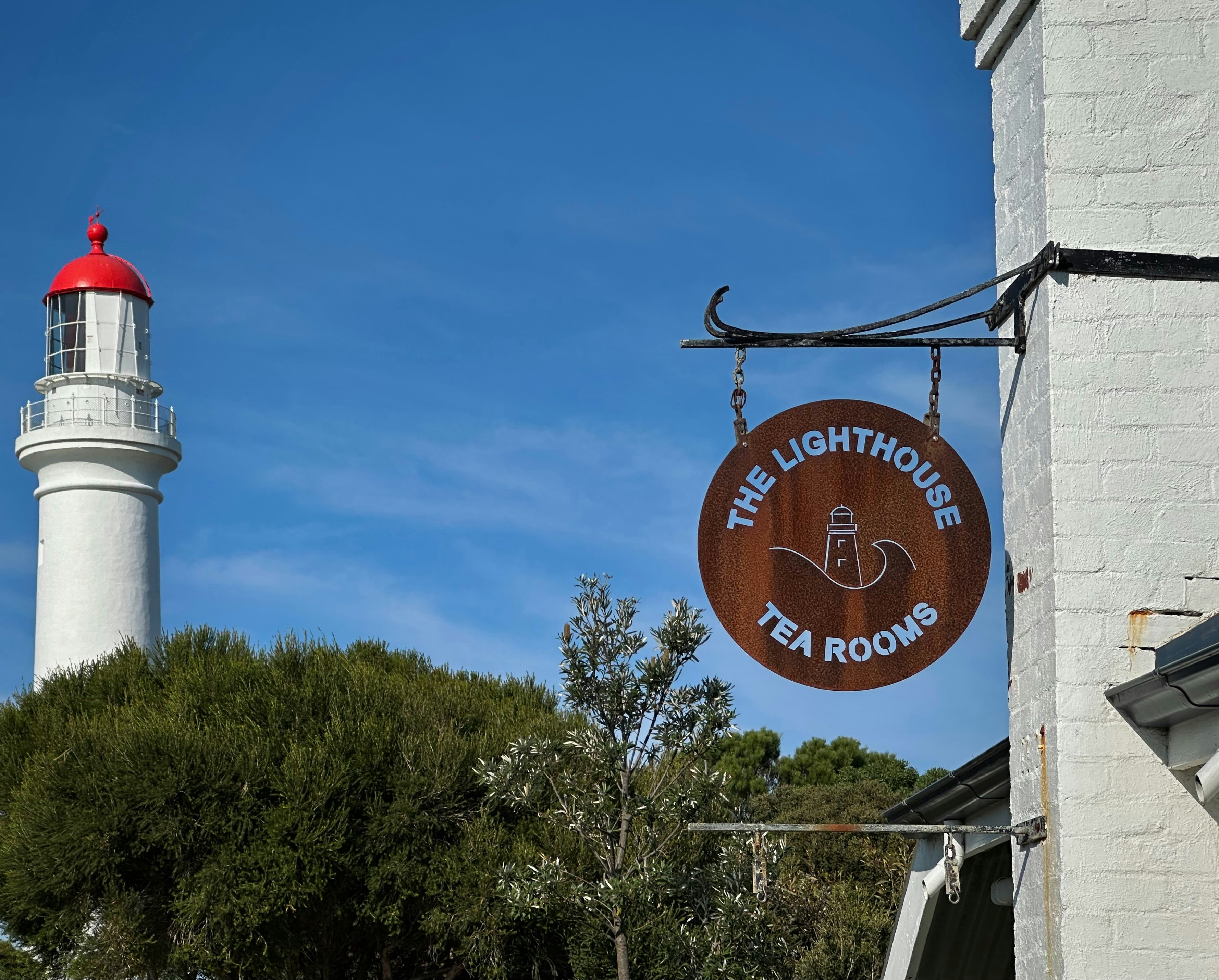 Lighthouse Sentinel and Teahouse Sign Against a Cerulean Sky