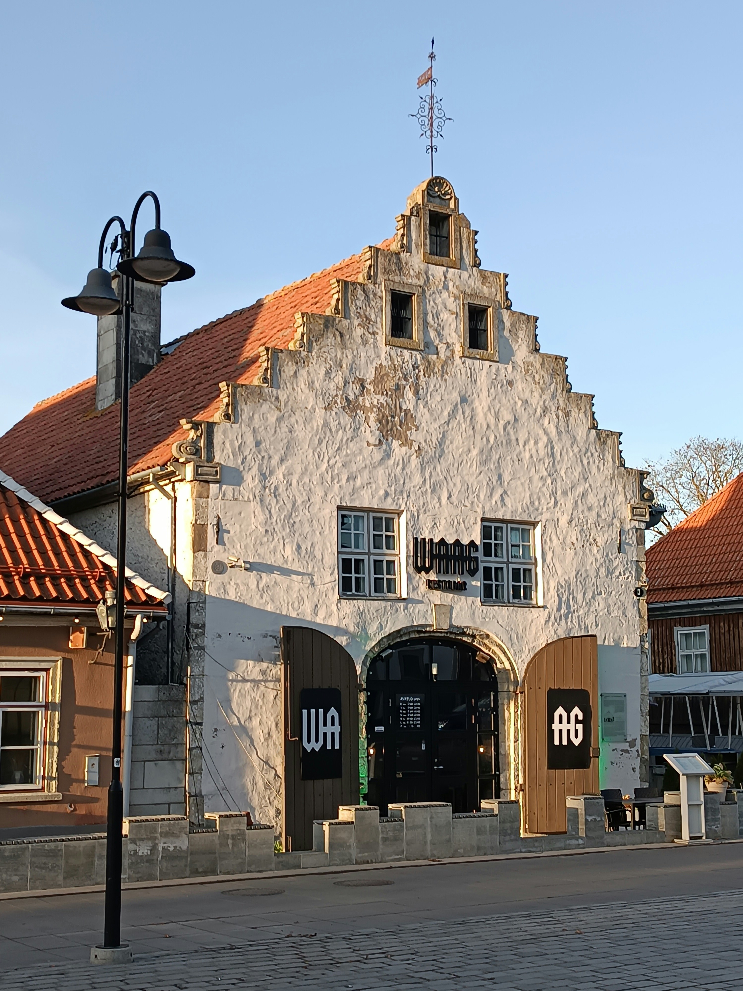 Historic building with a distinctive gabled roof and modern signage, set against a clear blue sky. The structure showcases a blend of traditional and contemporary design elements.