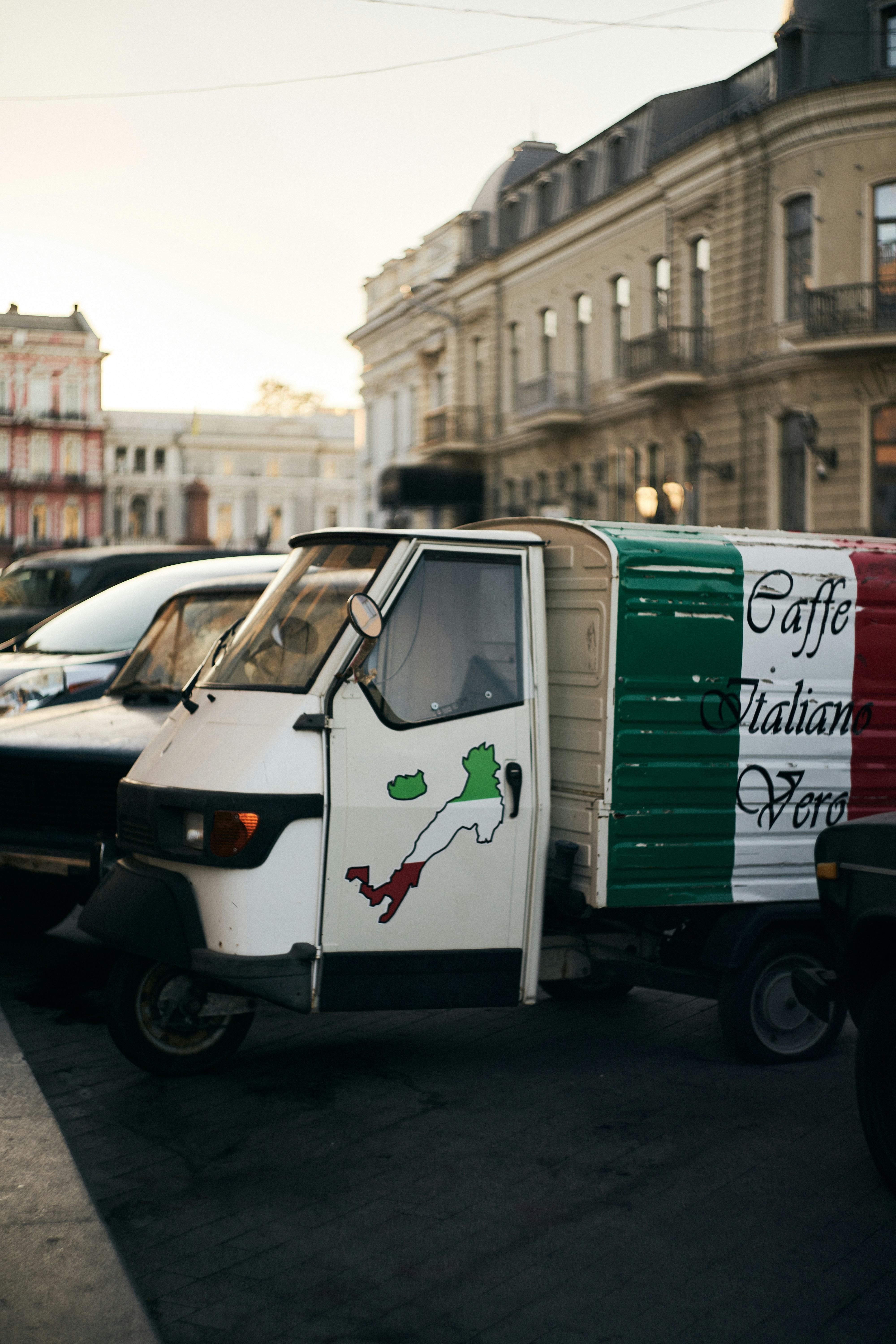 Caffe Italiano on Wheels: A white-and-green delivery van resting along a sunlit European street
