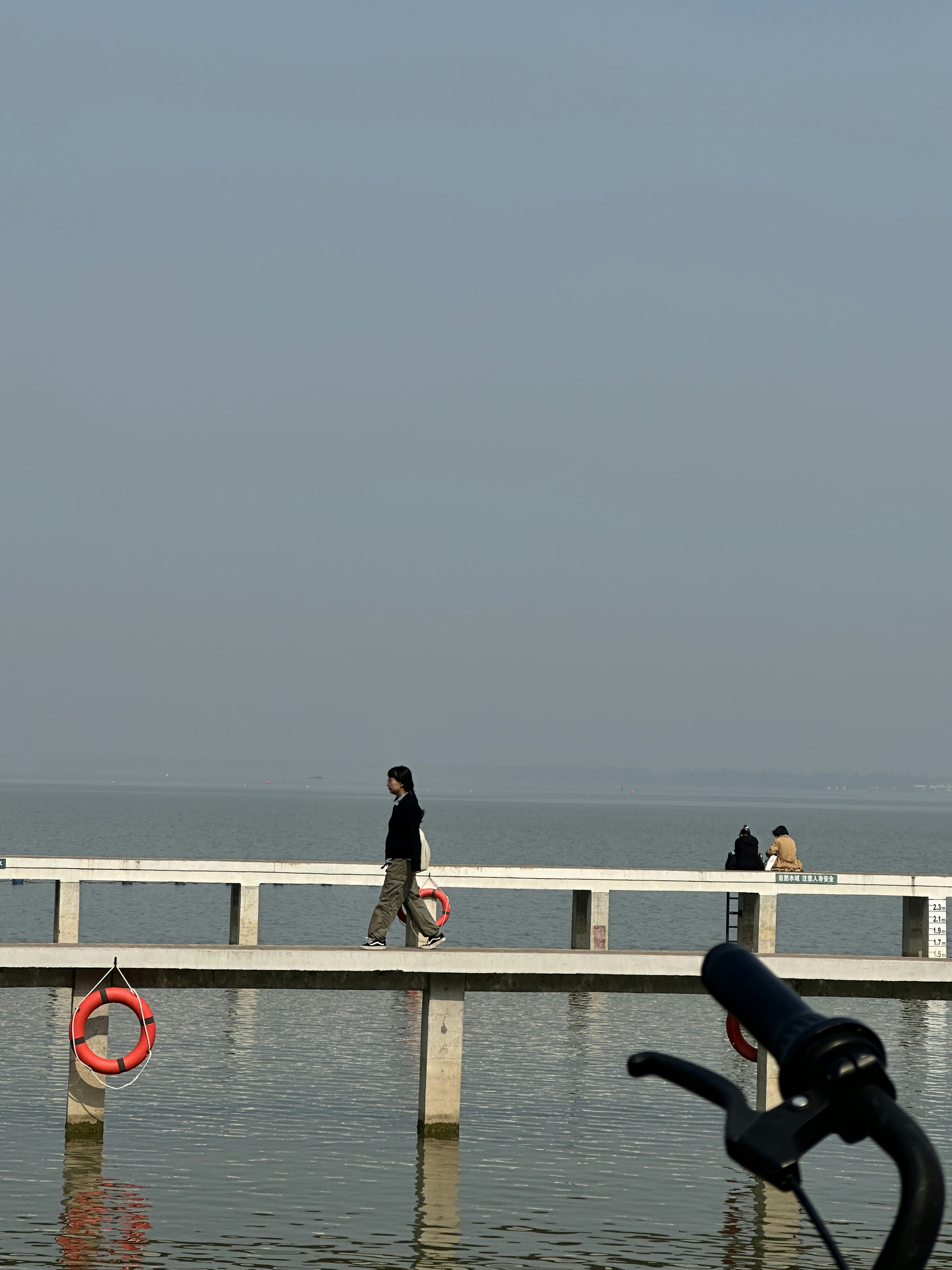 Lone Figure on the Pier Beneath a Vast Harbor Sky