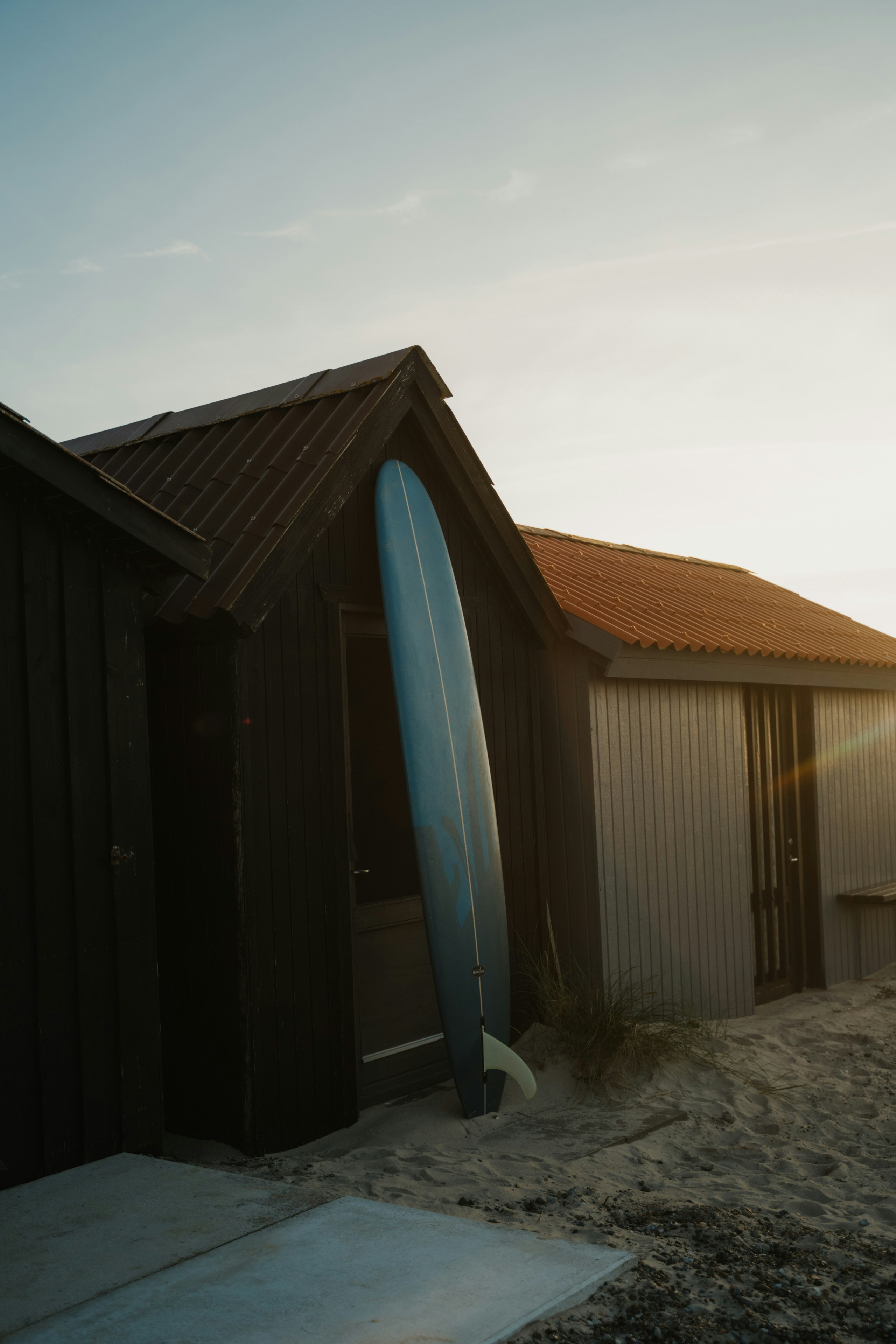 A surfboard leaning against a building on a beach photo – Free Outdoors ...
