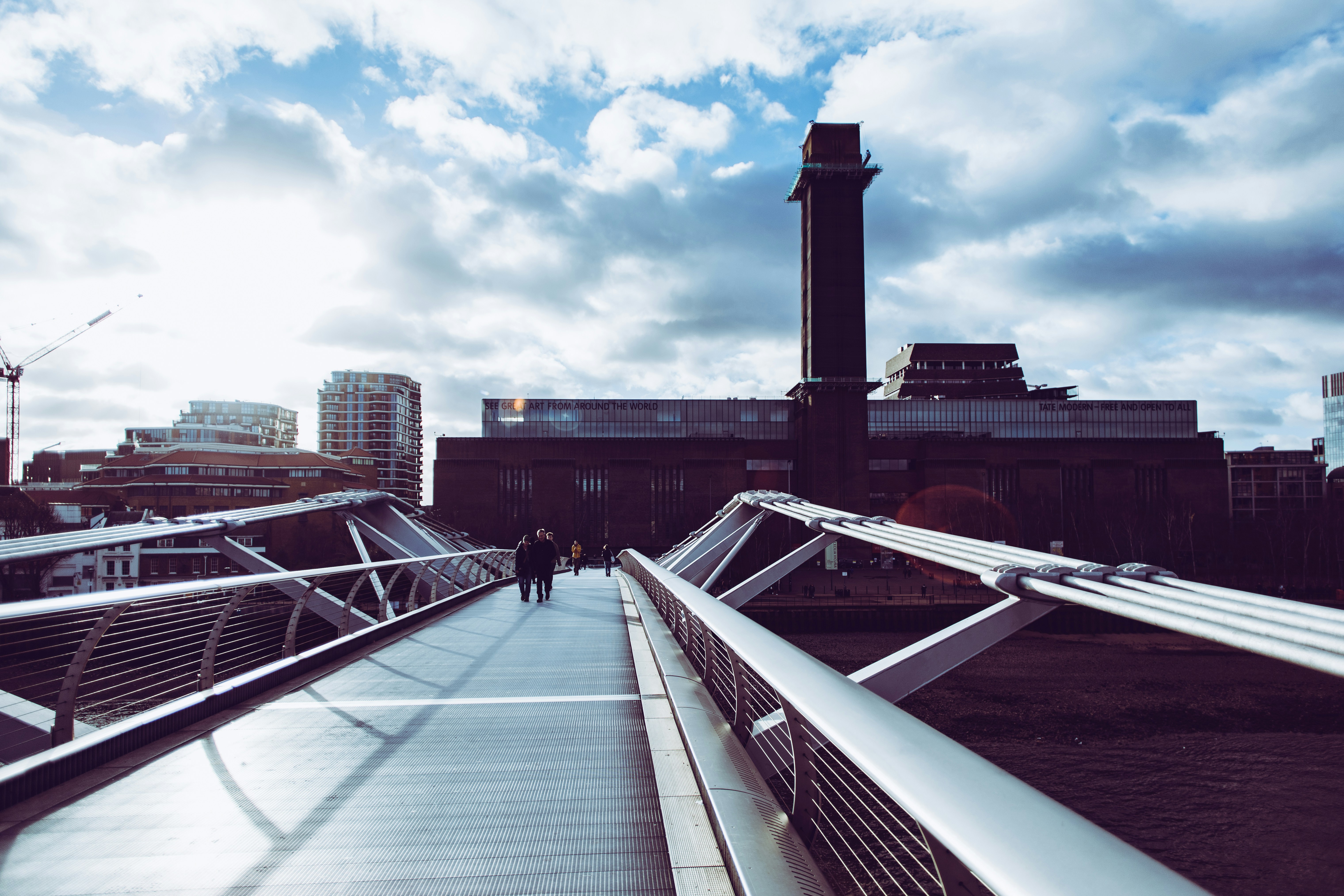 A person walking across a bridge in a city photo – Free Tate modern ...