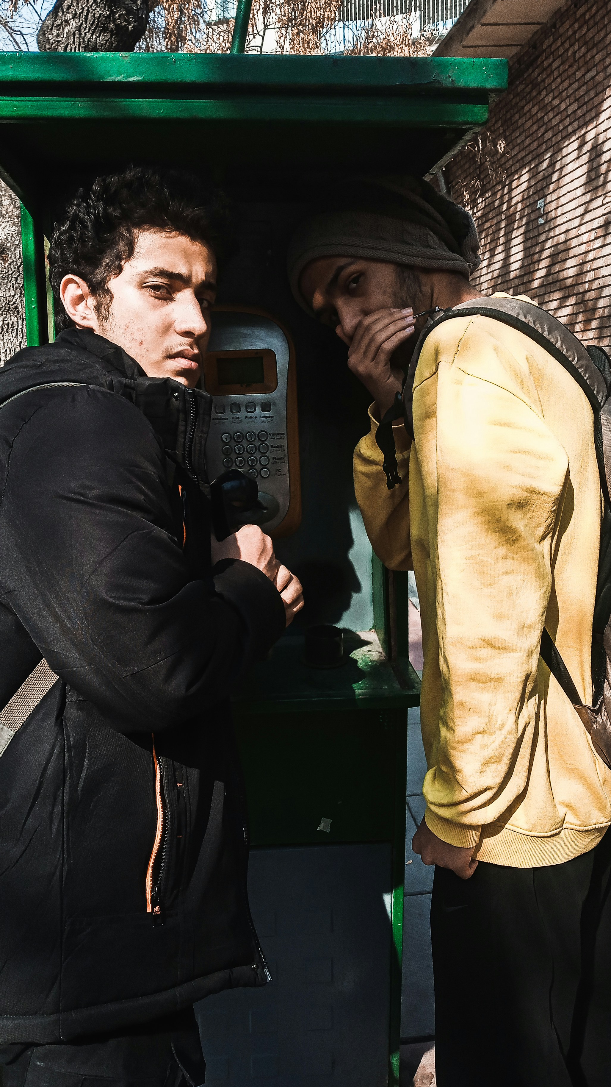 Two Faces at the Payphone: A Quiet Moment Between Strangers