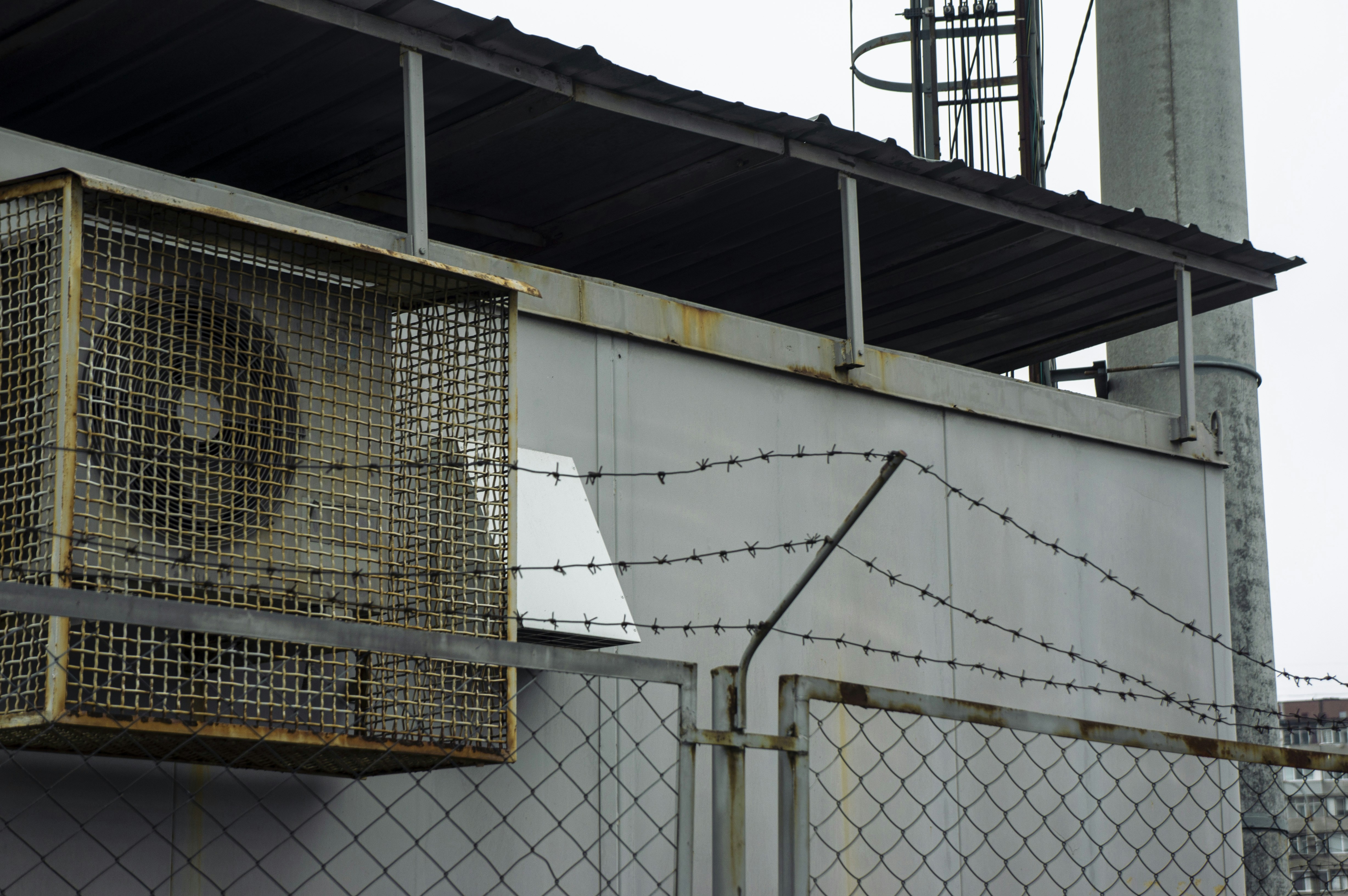 Caged Vent on a Rooftop: Barbed Wire and Concrete Quiet