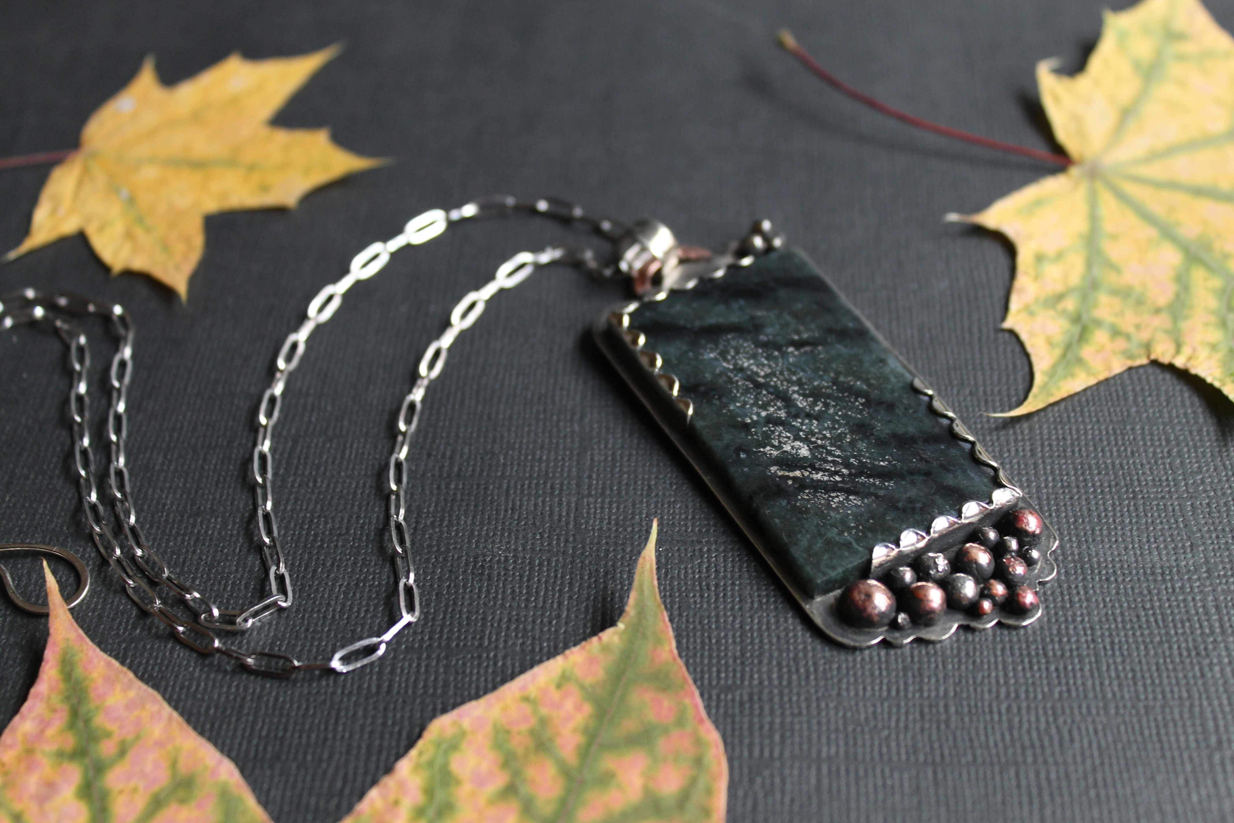 Metallic Pendant Resting Among Autumn Leaves