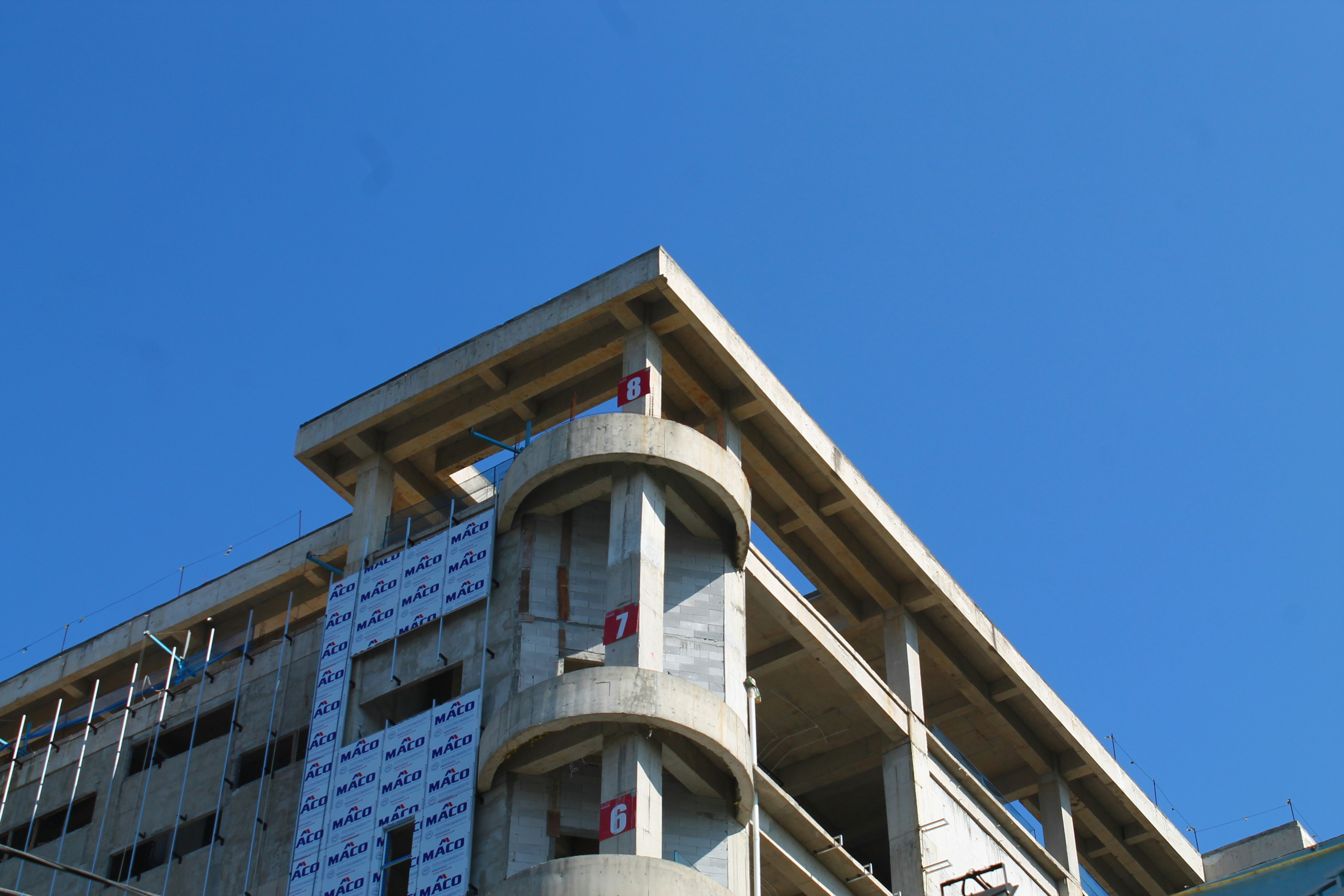 Concrete building with angular features and cylindrical columns under a vivid blue sky.