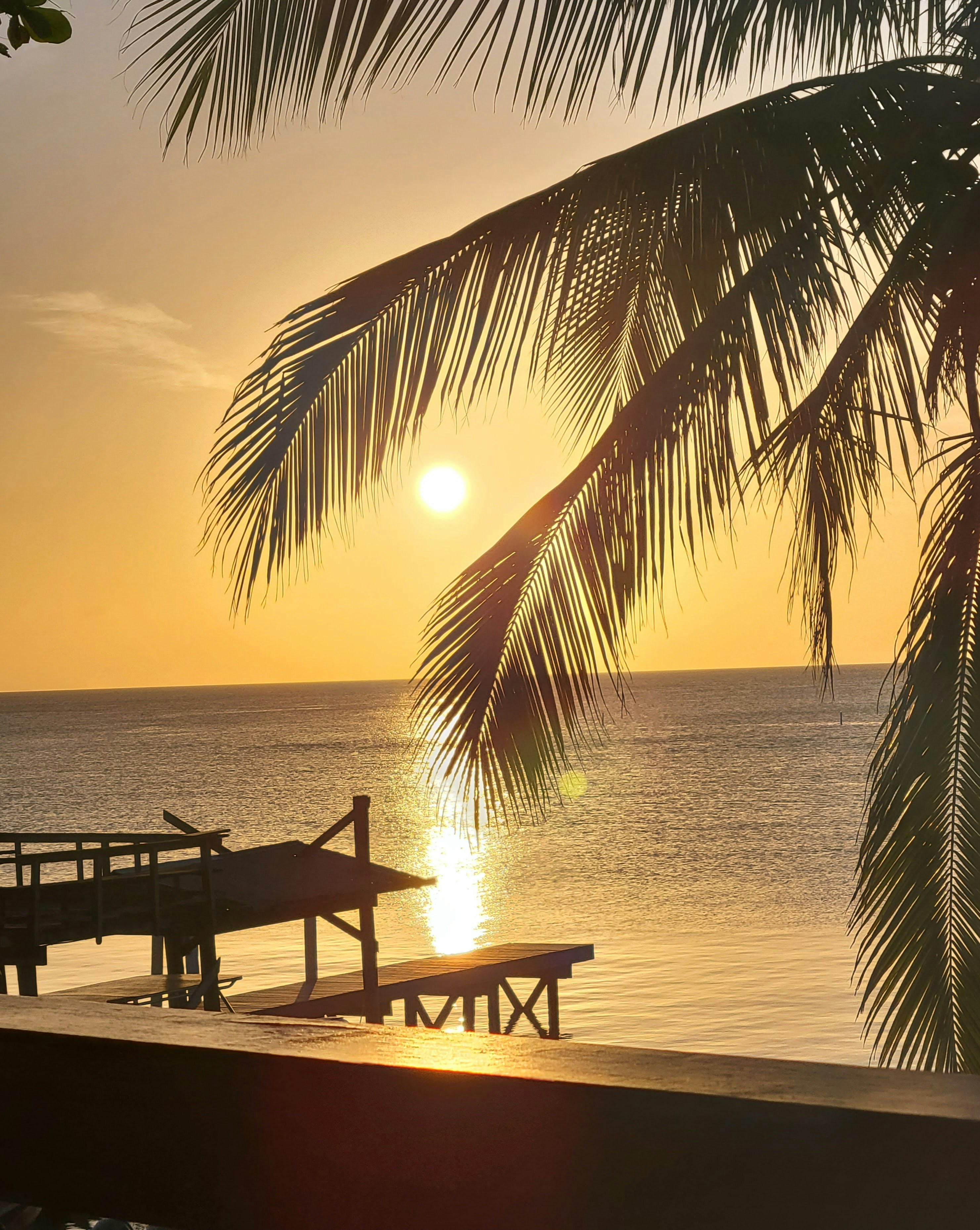 The sun is setting over the water and a dock photo – Free Roatán Image ...