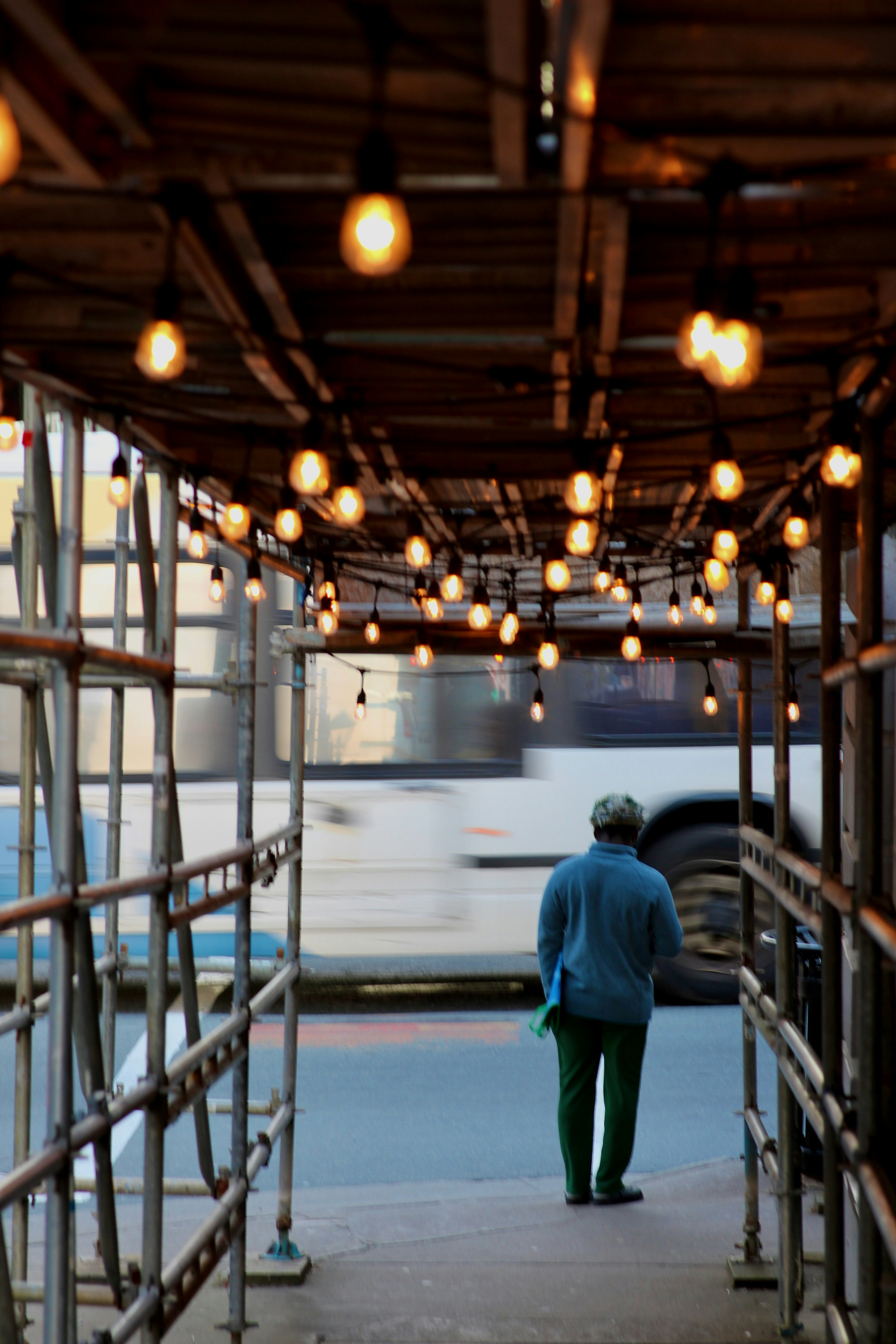 Lantern-Glow Corridor: A Solitary Figure Under Scaffold Lights