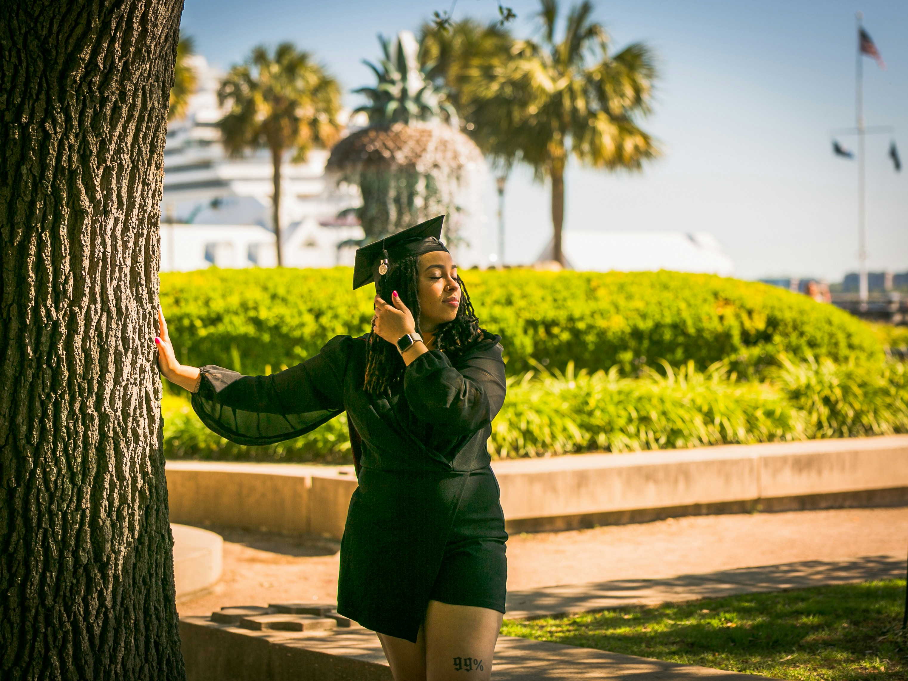 A woman in a graduation cap leaning against a tree photo – Free ...