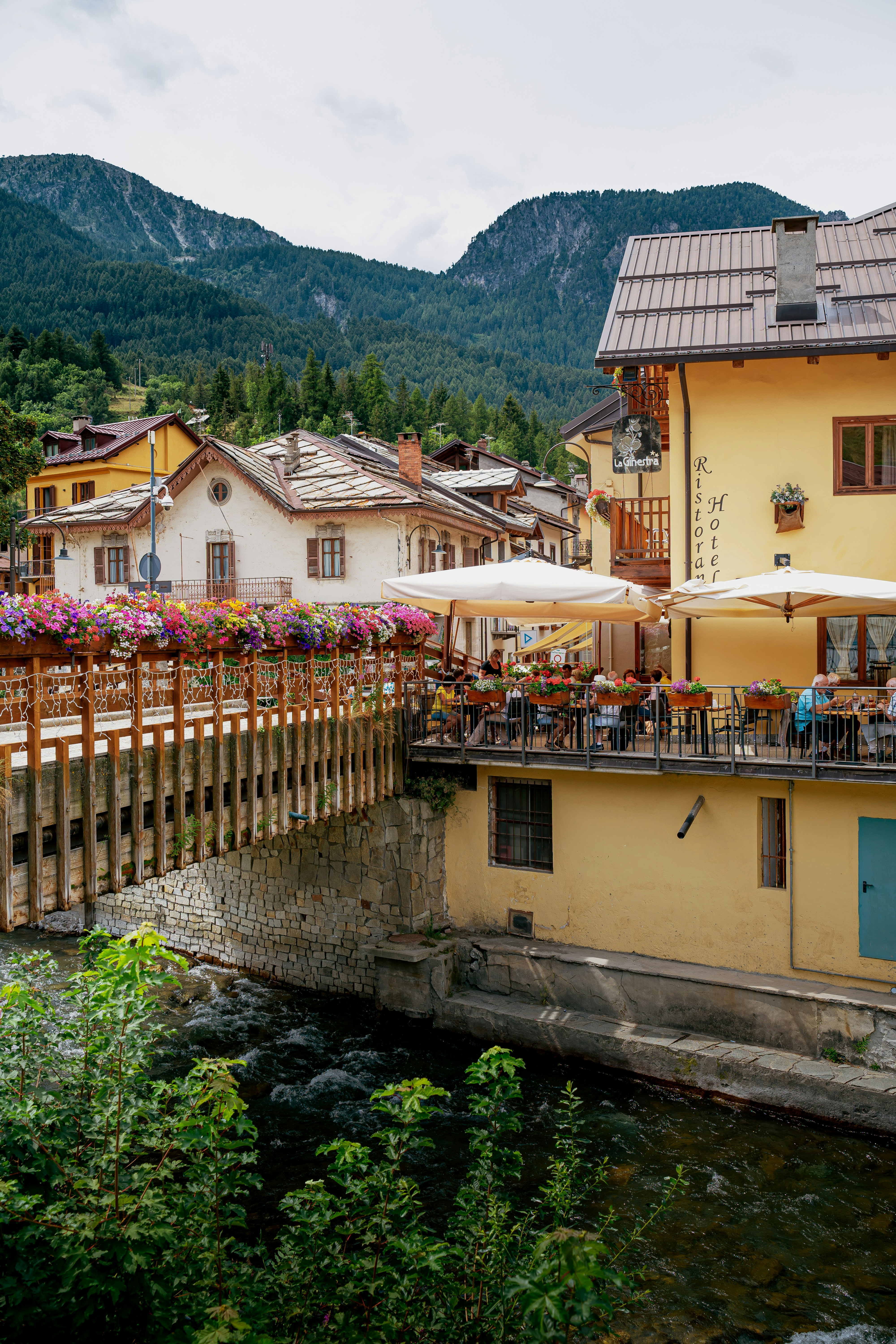 Terraced riverside café under Alpine sun