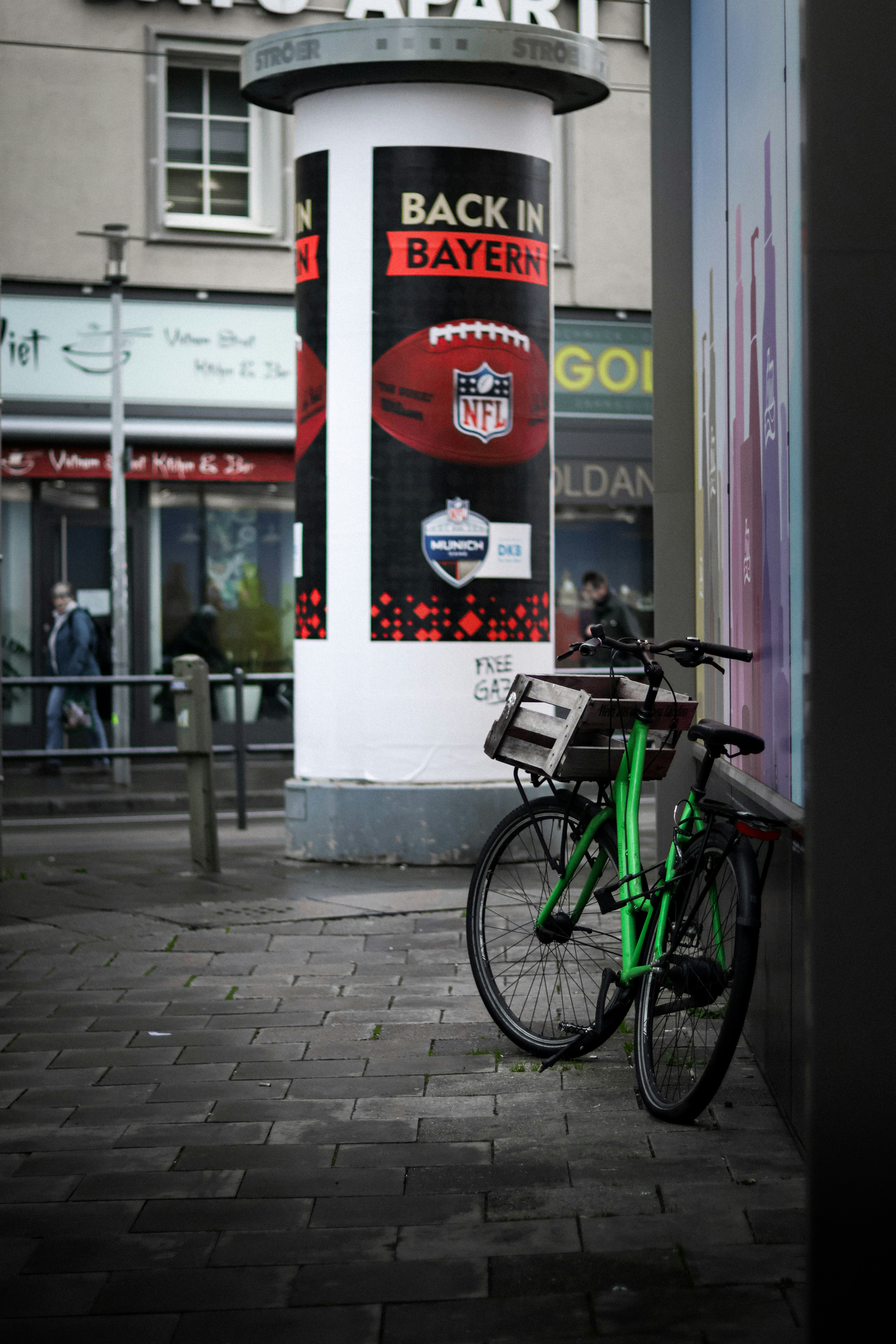Neon-Green Courier Bike Guards the NFL Poster Column in a City Scene