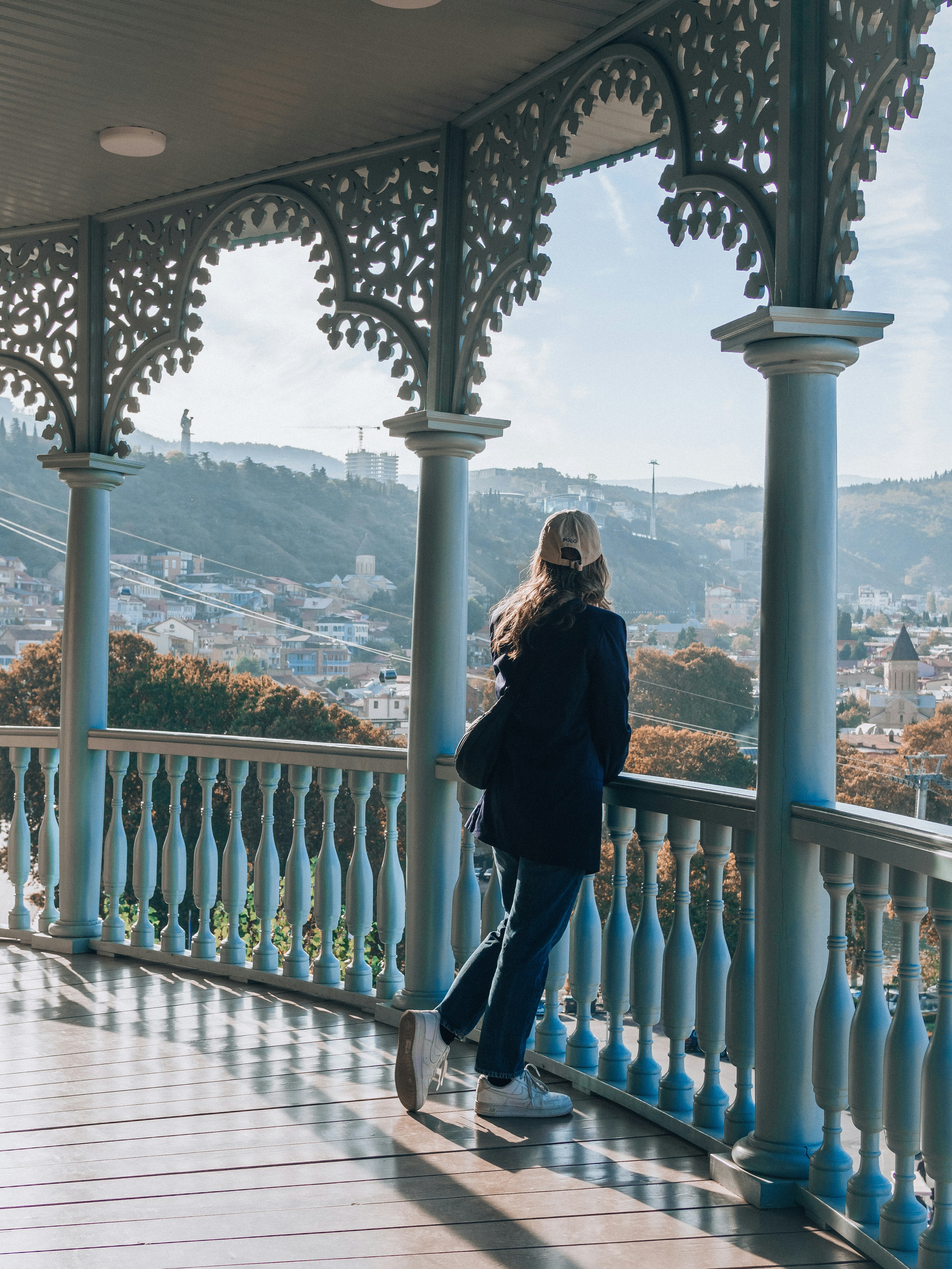 A woman standing on a balcony with a view of a city