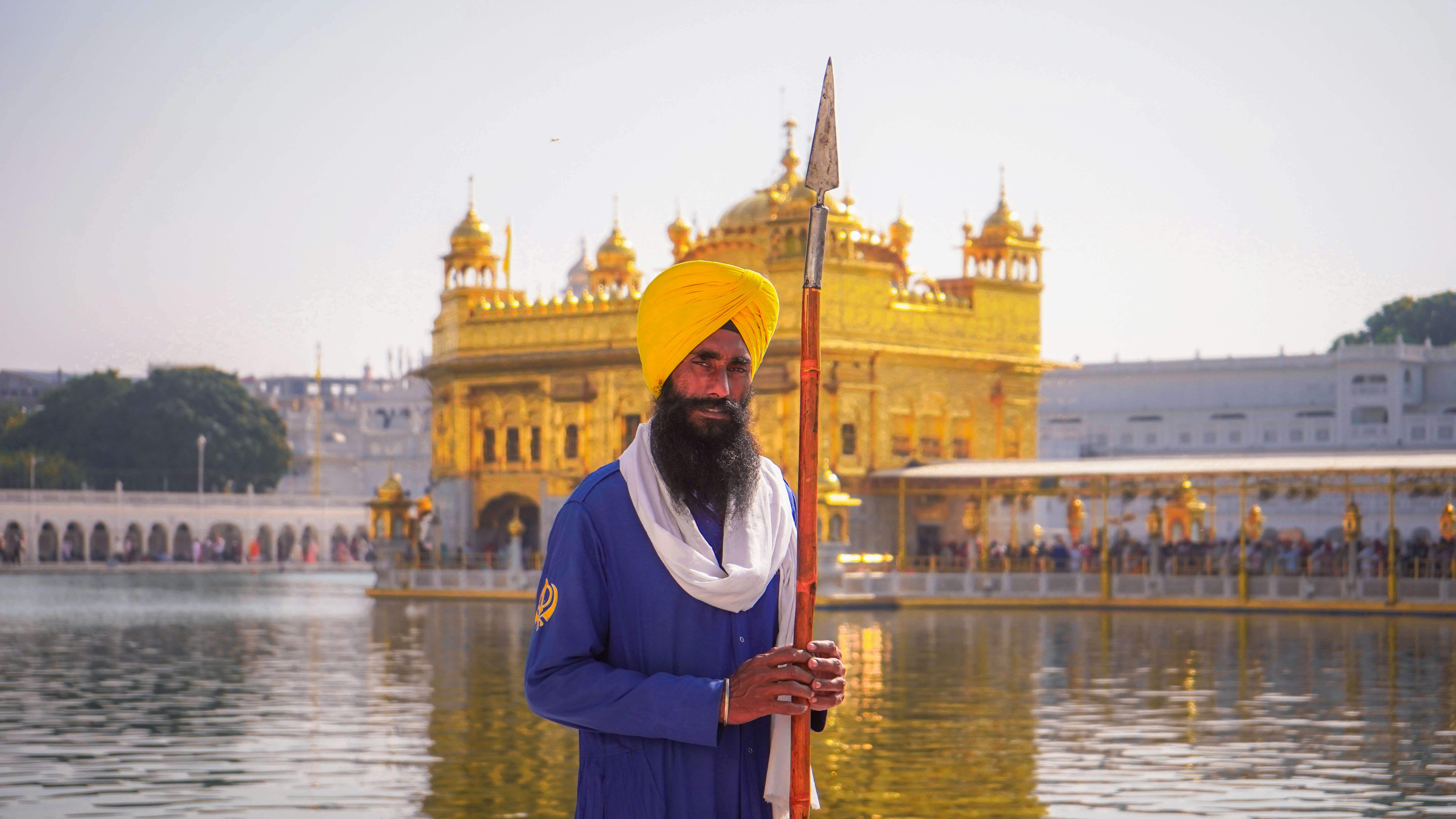 Blue-robed pilgrim by Harmandir Sahib, framed by the Golden Temple's gilded facade