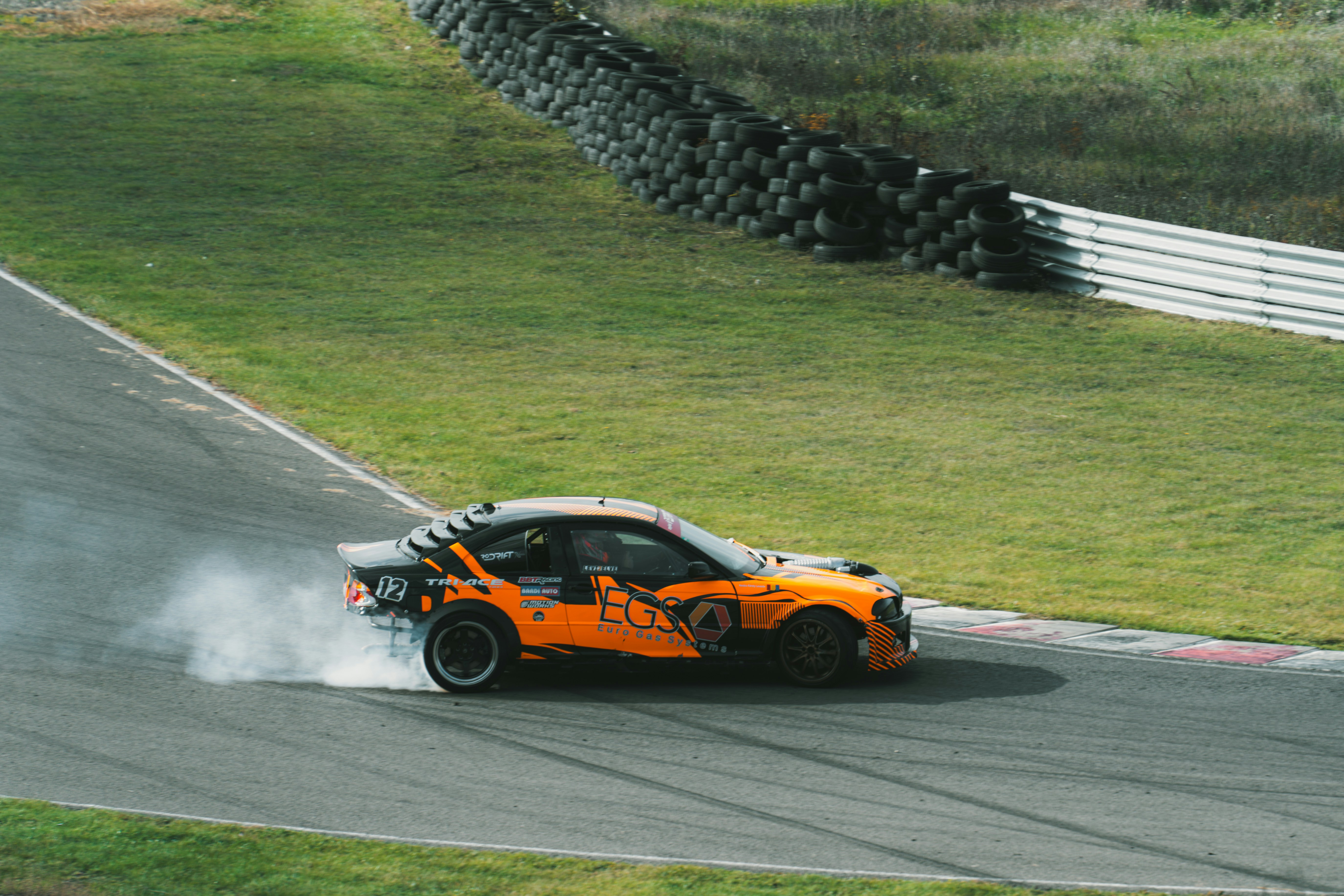 Drift in Orange: Smoke Trails and Speed on a Sunny Racetrack
