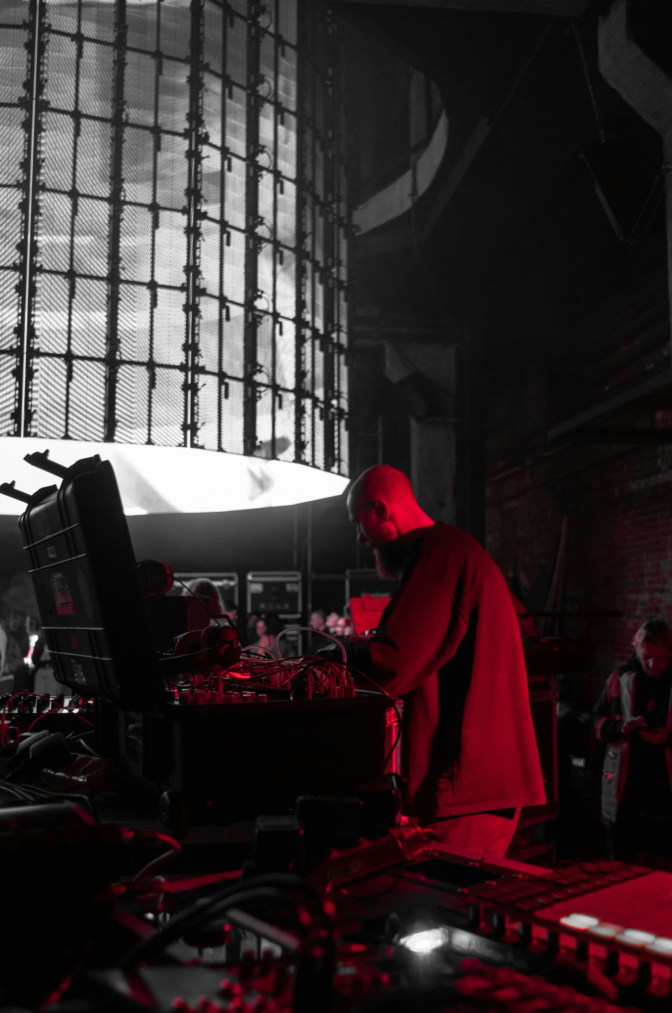 Red Light Rhythm: DJ at the Console in Dim Warehouse