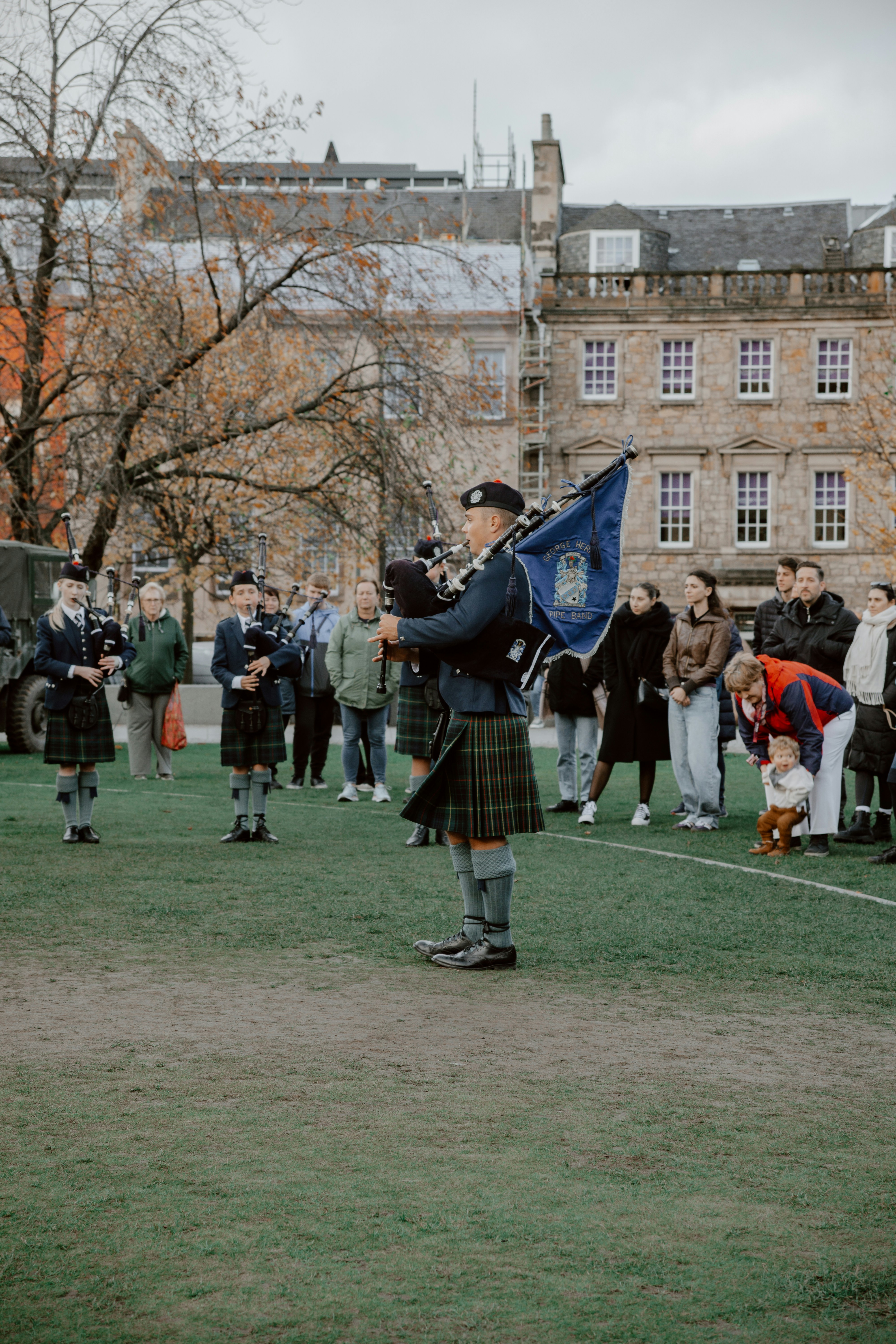 Highland Piper in the City Park: Tradition Amid Curious Onlookers