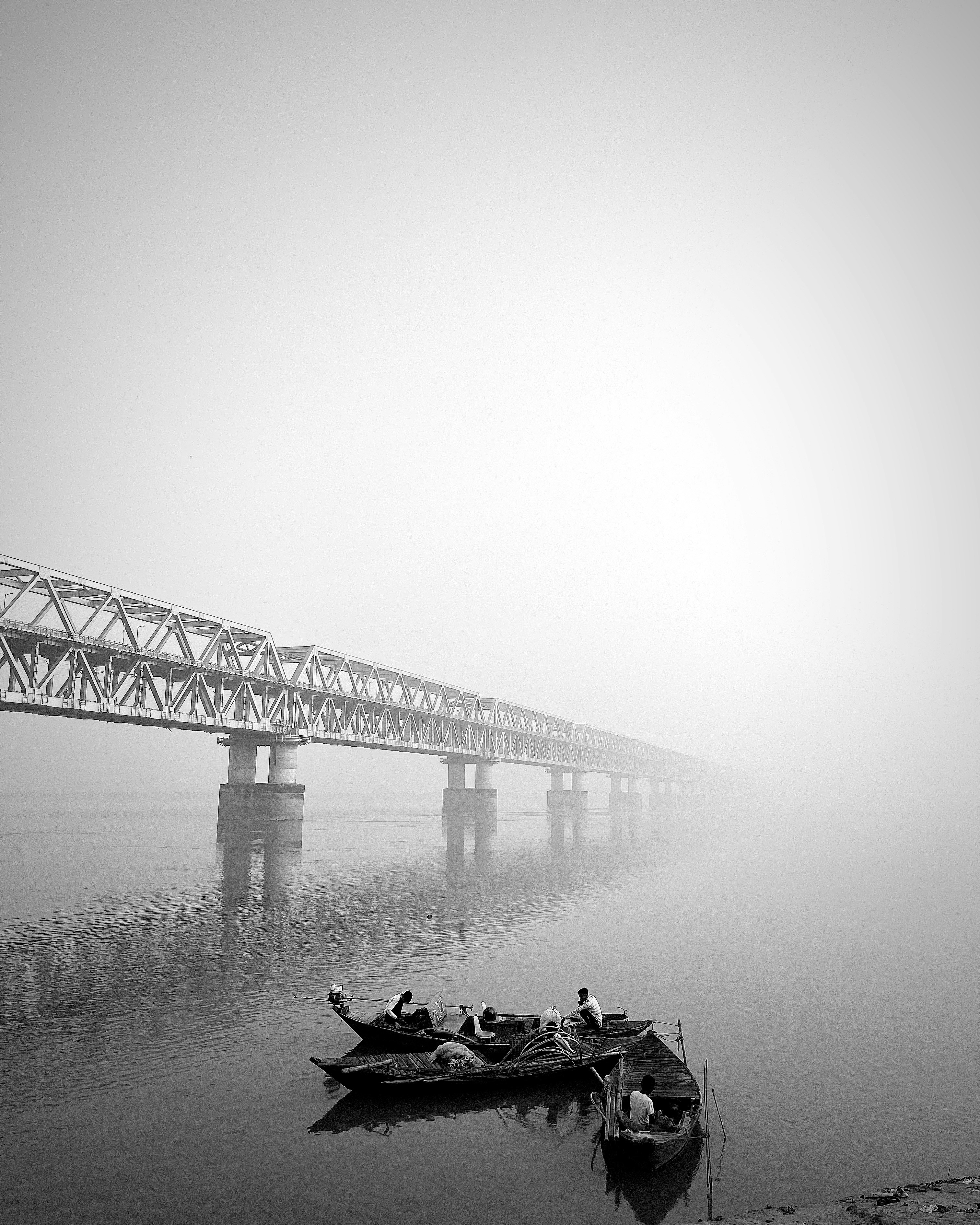 Mist-Lined Crossing: Boats Rest at the Foot of a Fogbound Bridge