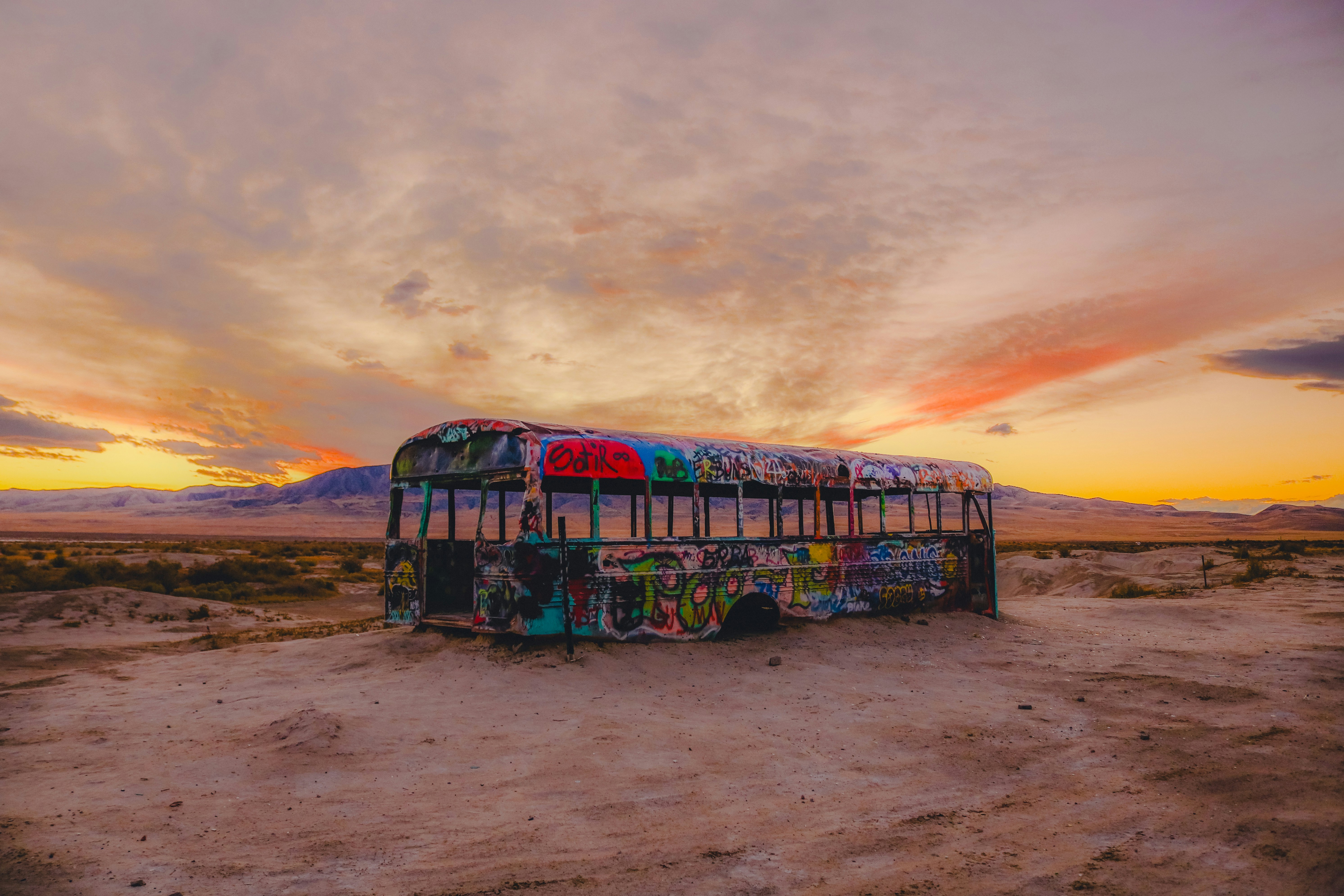 Graffiti Bus at Desert Sunset: Neon Flares on Parched Ground